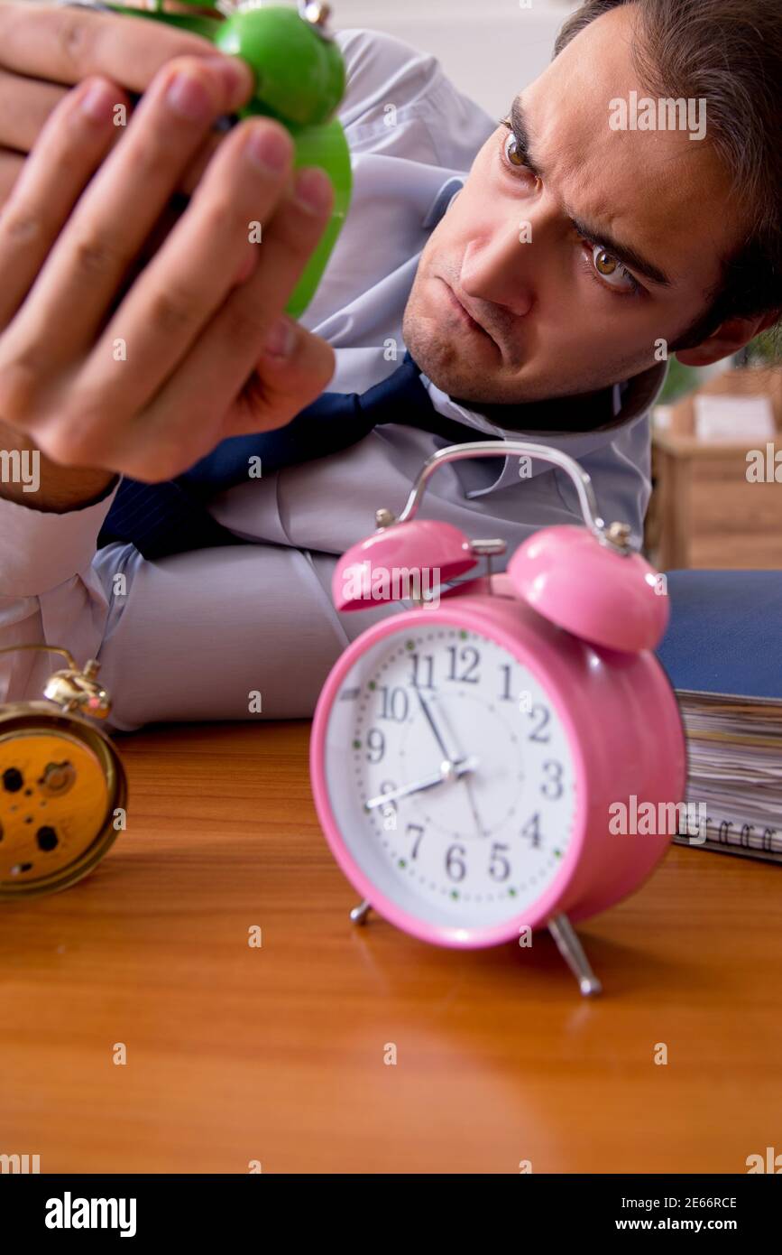 Young businessman sleeping in the office in time management concept ...