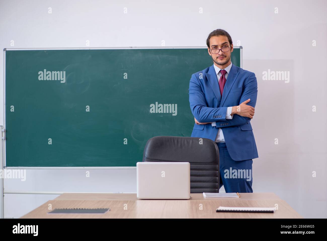 Young teacher in suit in front of green board Stock Photo - Alamy