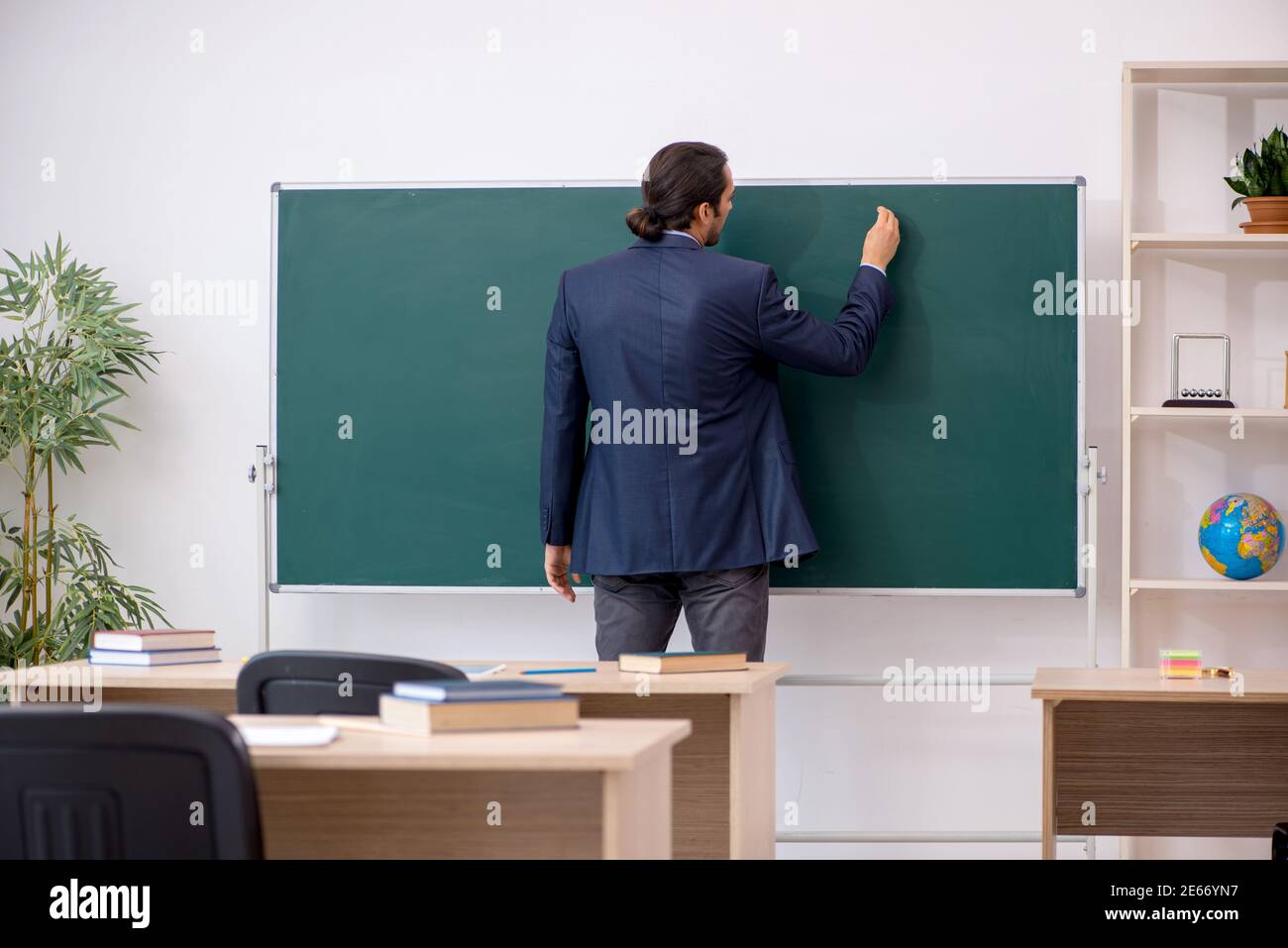 Young teacher in front of green board Stock Photo - Alamy