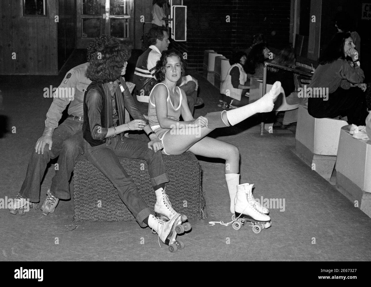 Young woman putting on knee pads before skating at Flipper’s Roller ...