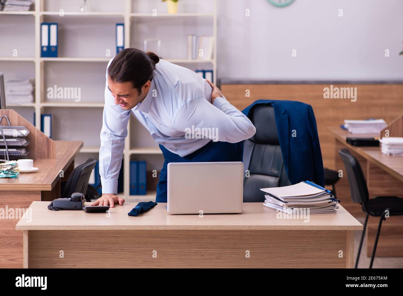 Young employee suffering from backpain at workplace Stock Photo - Alamy