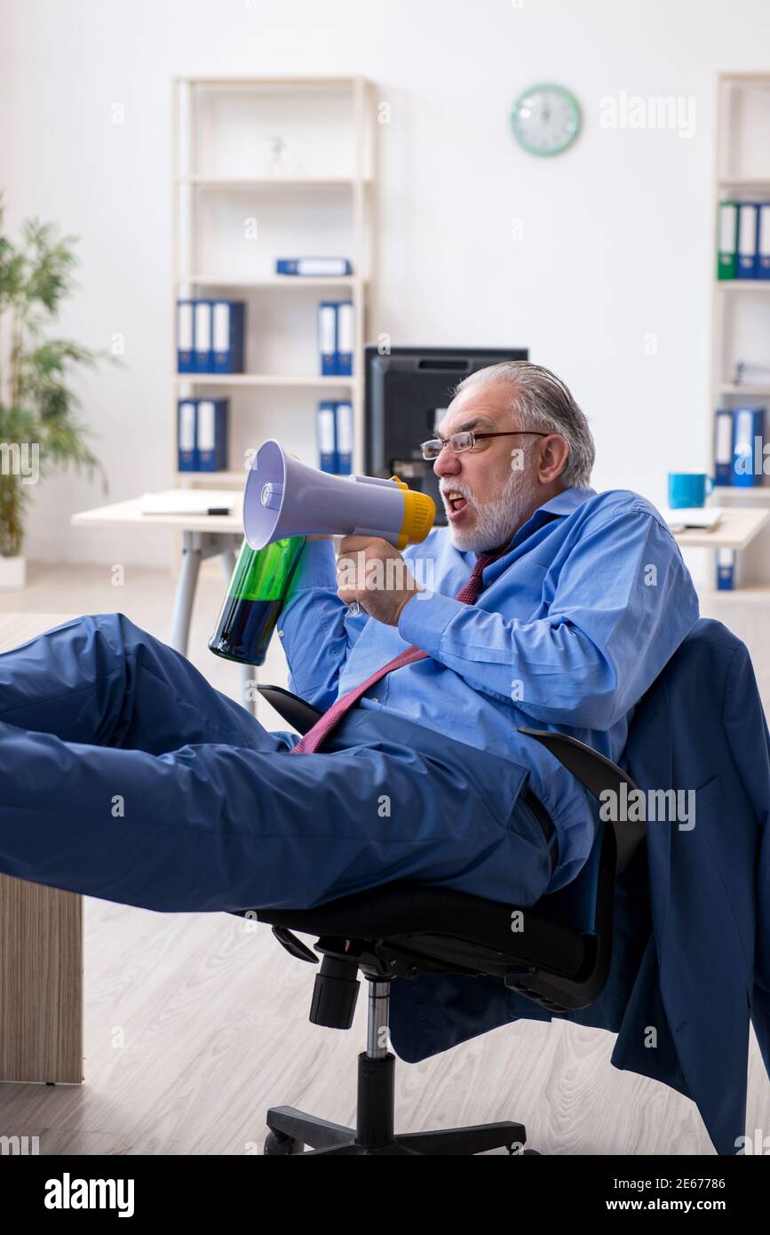 Senior male employee drinking alcohol in the office Stock Photo - Alamy