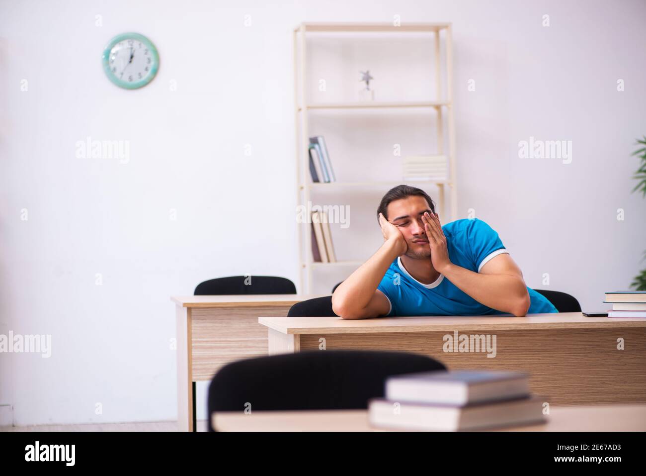 Exhausted student preparing for the exams in the classroom Stock Photo ...