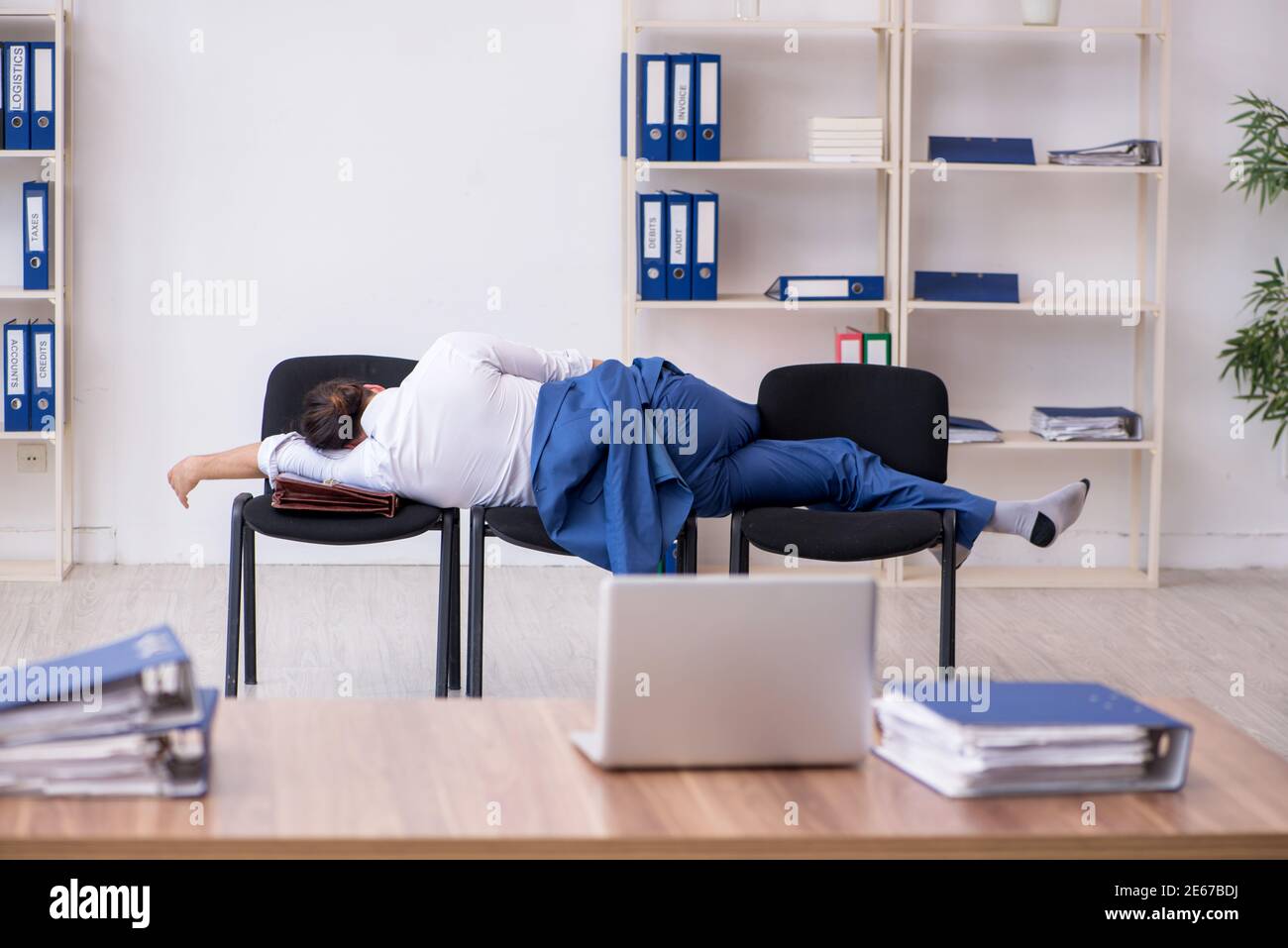 Young employee sleeping in the office on chairs Stock Photo - Alamy