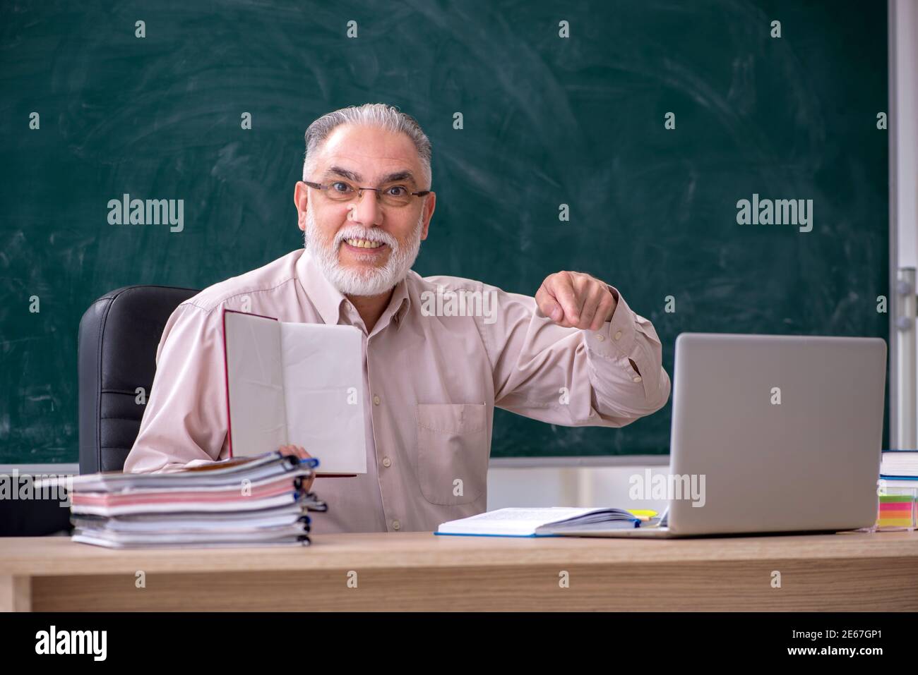 Senior male teacher sitting in the classroom Stock Photo - Alamy