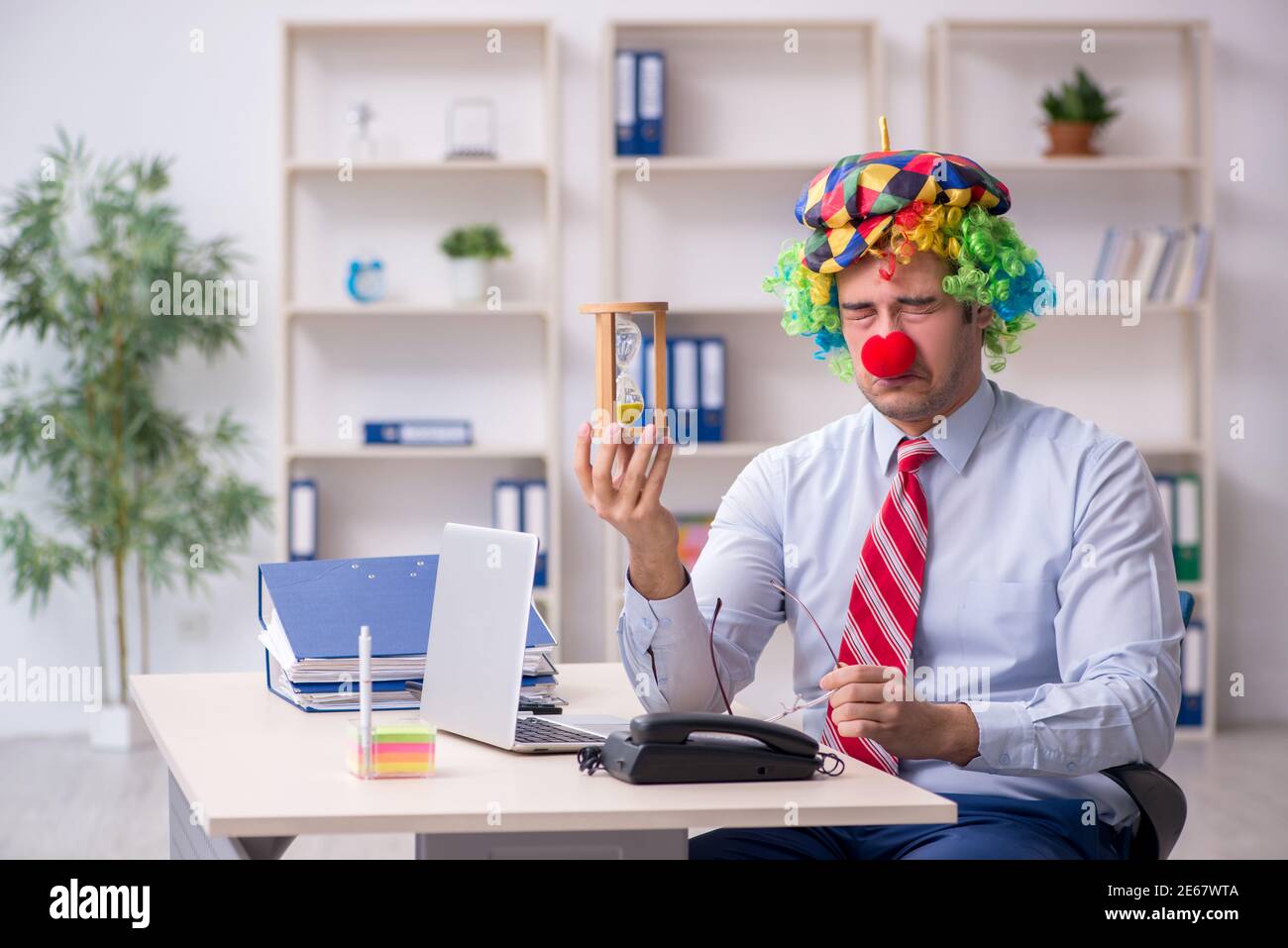 Funny employee clown working in the office room Stock Photo - Alamy