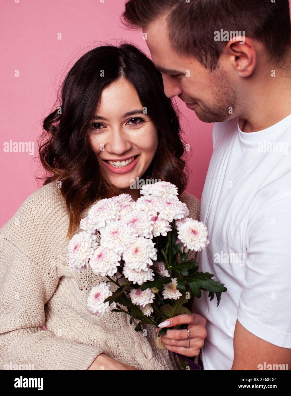 young cheerful caucasian couple together having fun on pink background ...