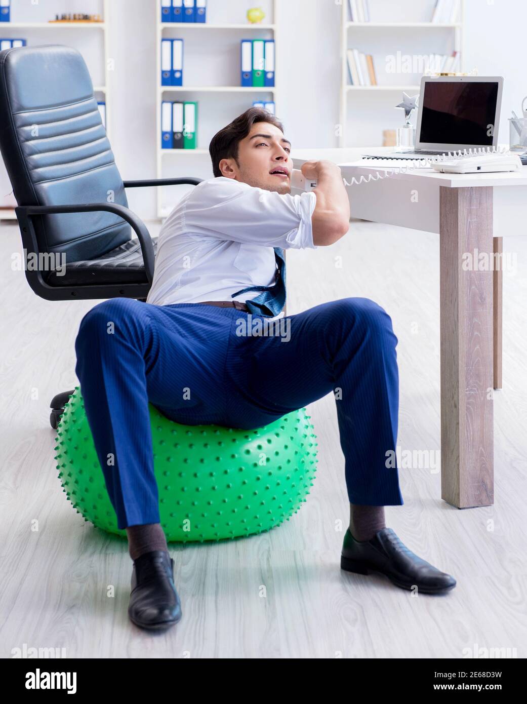 The young businessman doing sports stretching at workplace Stock Photo ...
