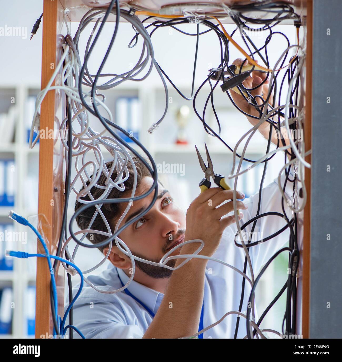 The electrician trying to untangle wires in repair concept Stock Photo ...