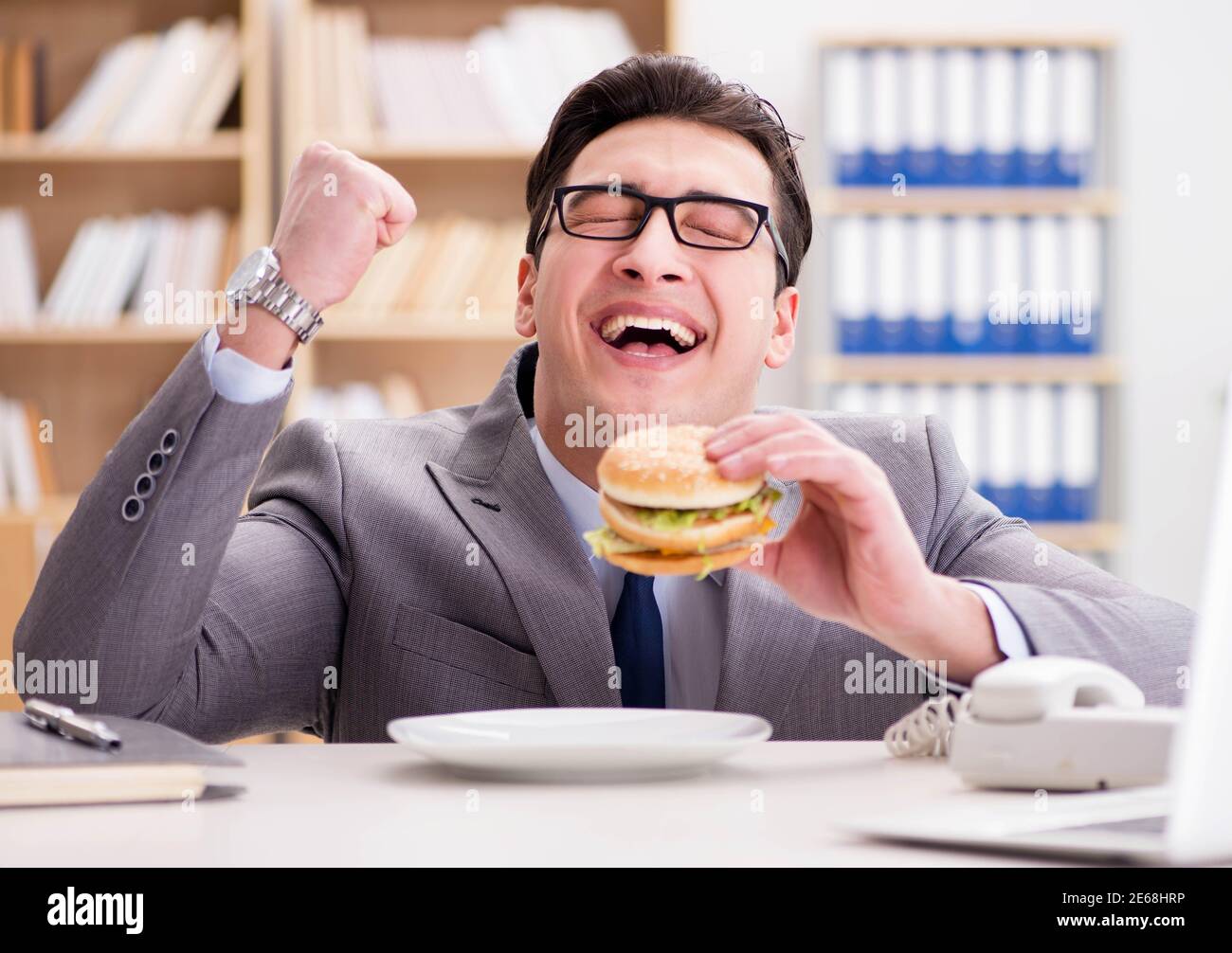 The hungry funny businessman eating junk food sandwich Stock Photo - Alamy