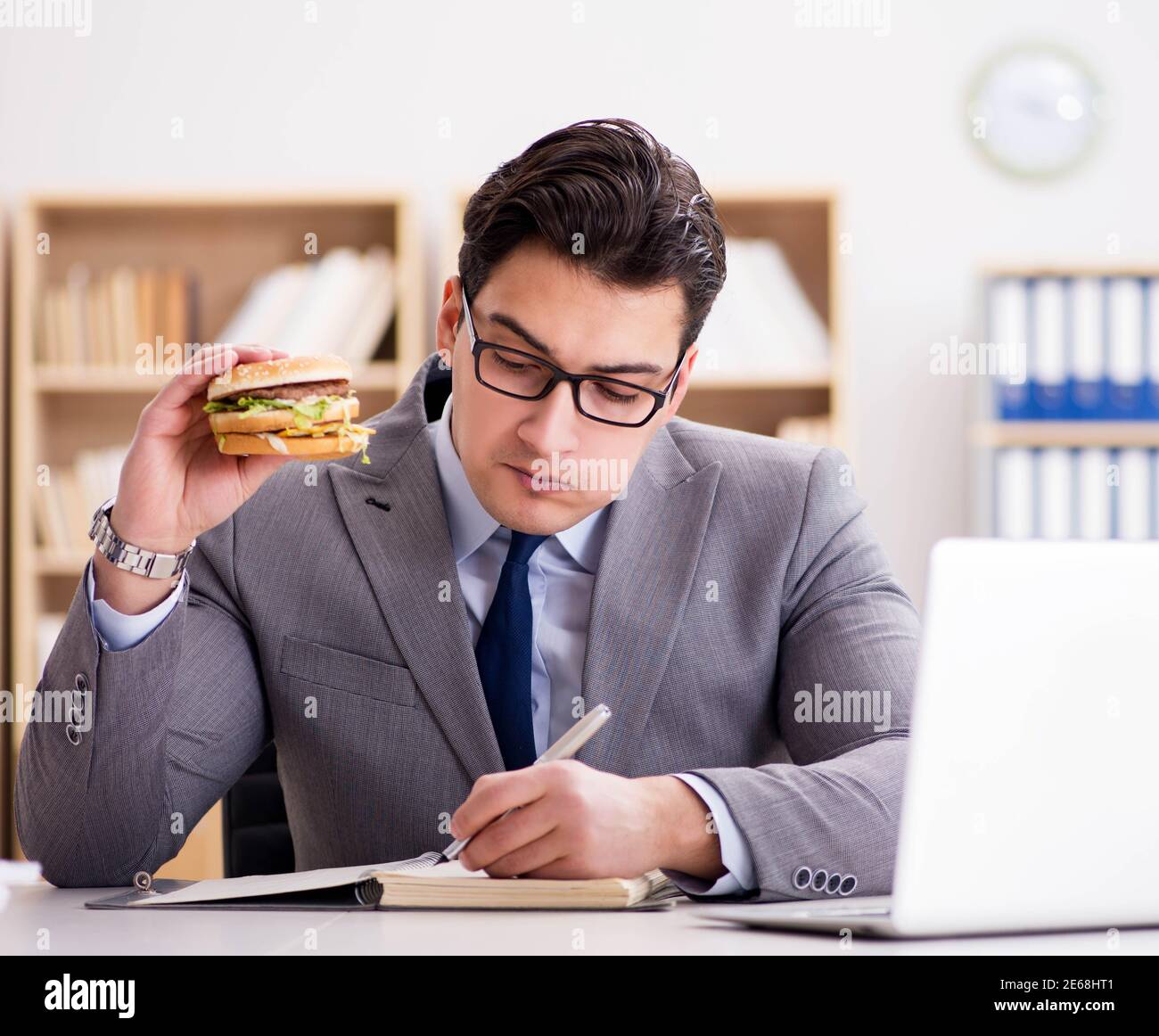 The hungry funny businessman eating junk food sandwich Stock Photo - Alamy