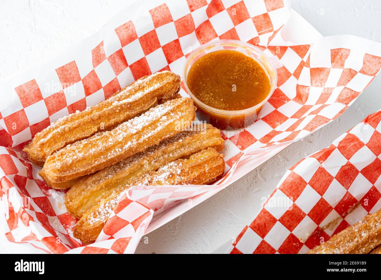 Tasty hot sweet churros in paper with chocolate, and caramel in paper ...