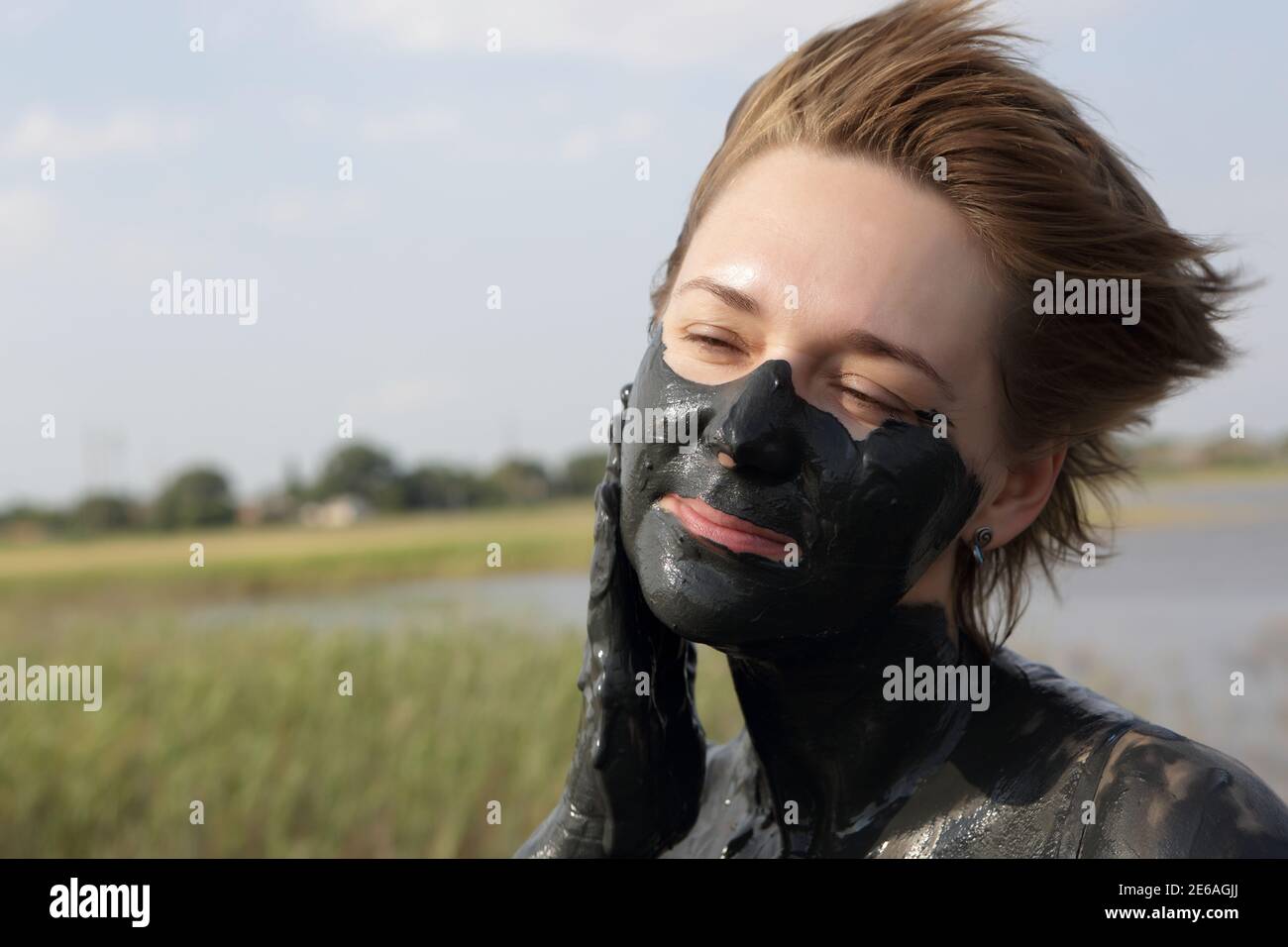 Woman applying mud on her face at firth Stock Photo - Alamy