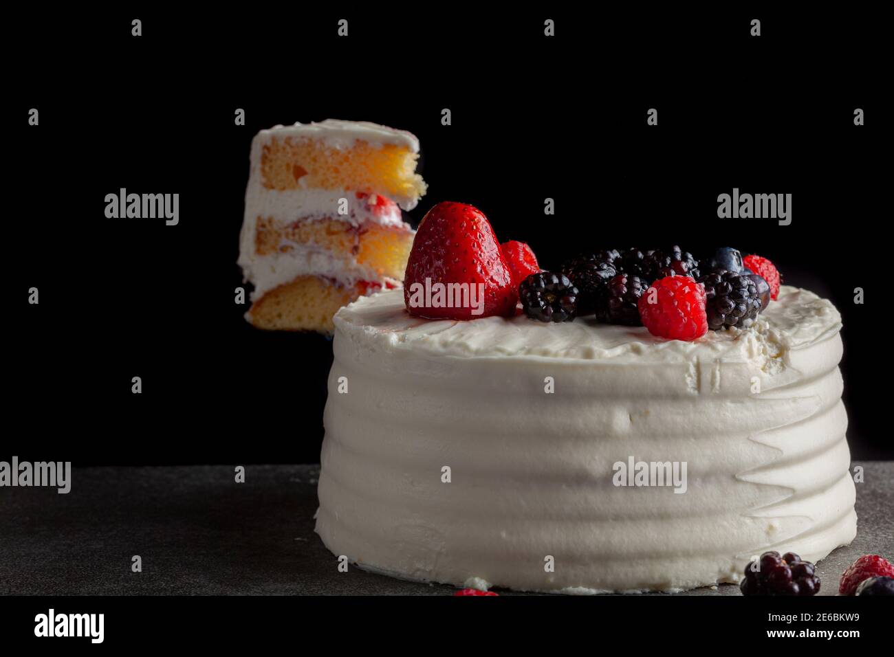 Close up image of a round cake with creamy white icing and assortment ...