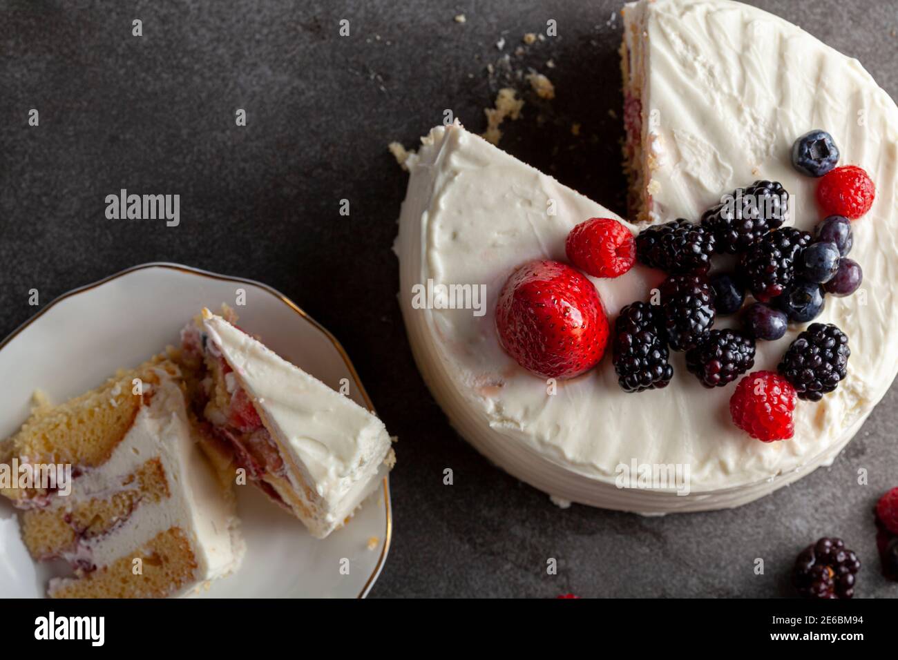 Flat lay image of a round cake with creamy white icing and assortment ...