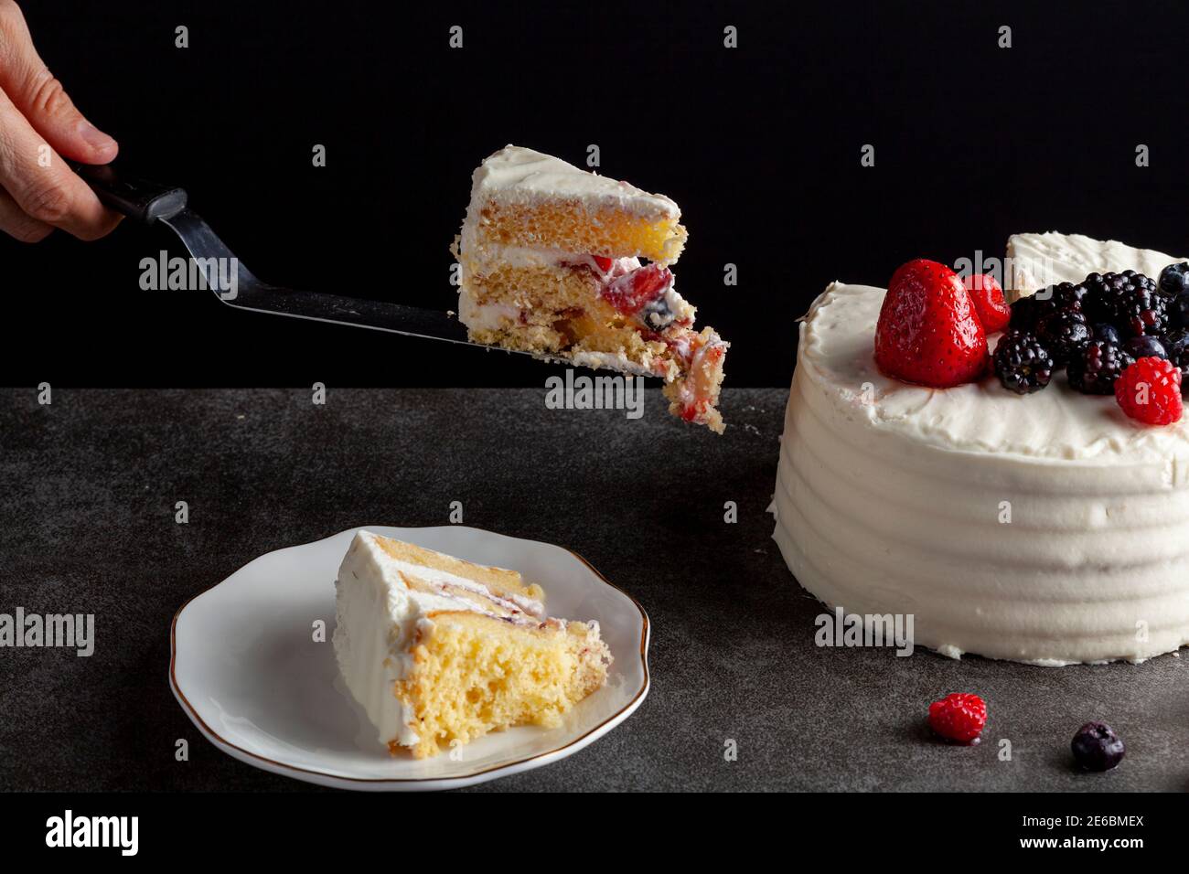 A round cake with creamy white icing and assortment of berries used as ...