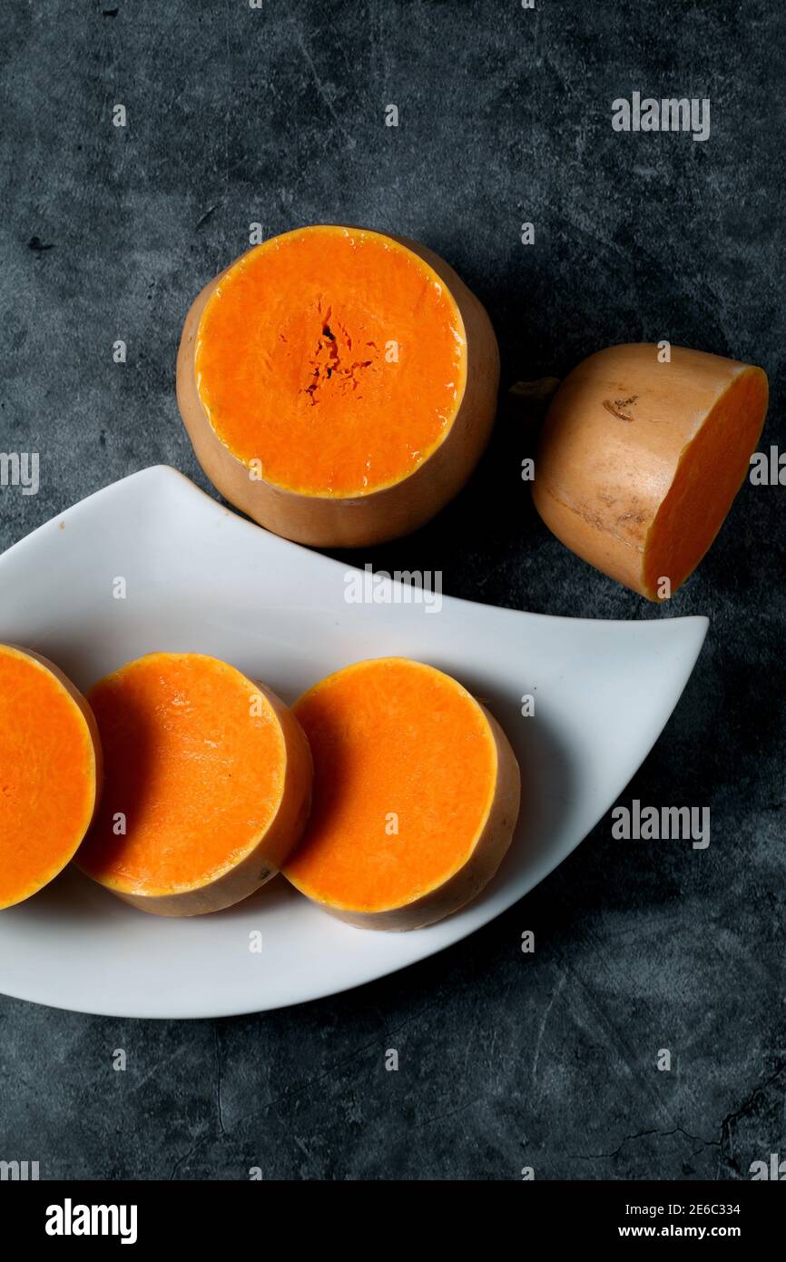 Vertical top view of sliced butternut squash on a white platter ...