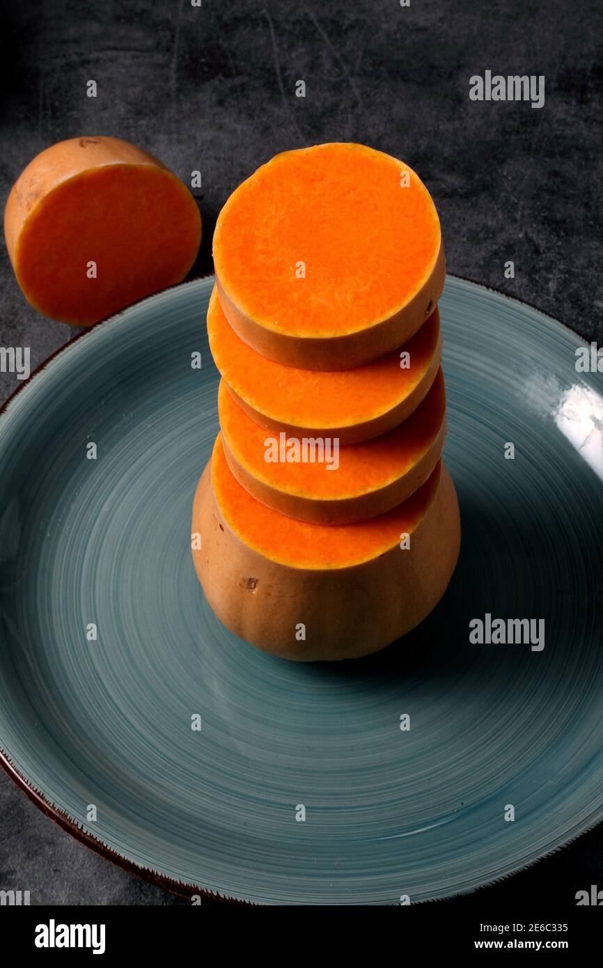 Vertical top view of sliced butternut squash on a plate isolated dark ...
