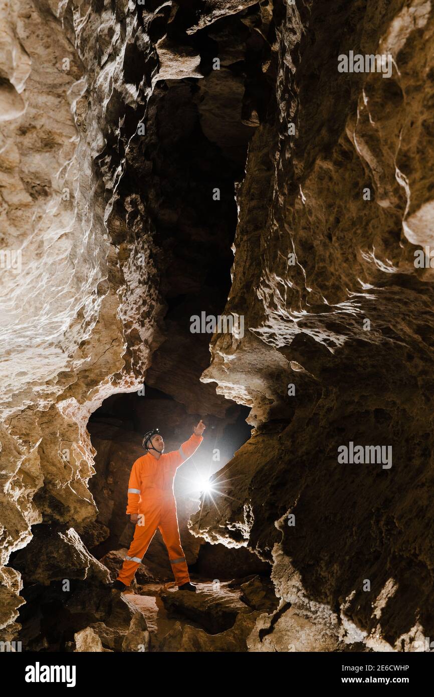 Man walking and exploring dark cave with light headlamp underground ...