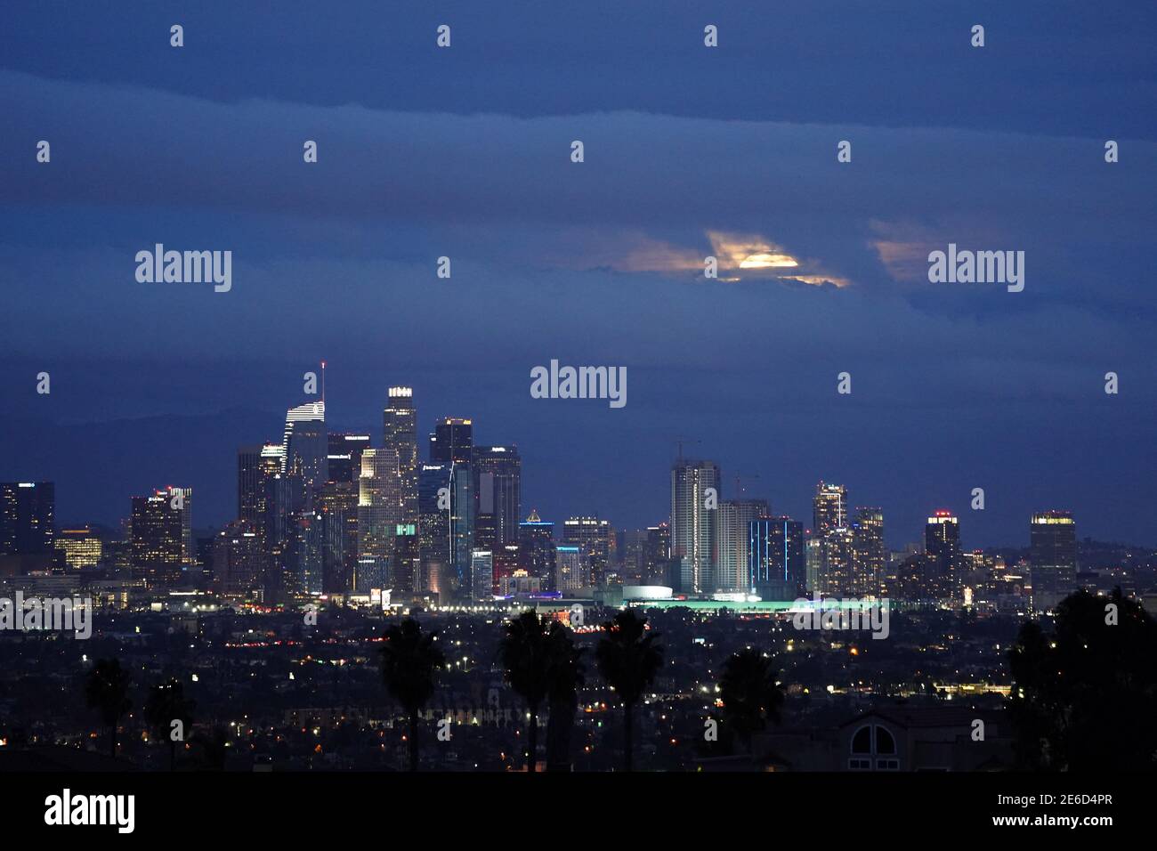 A full moon rises through storm clouds over the downtown Los Angeles ...