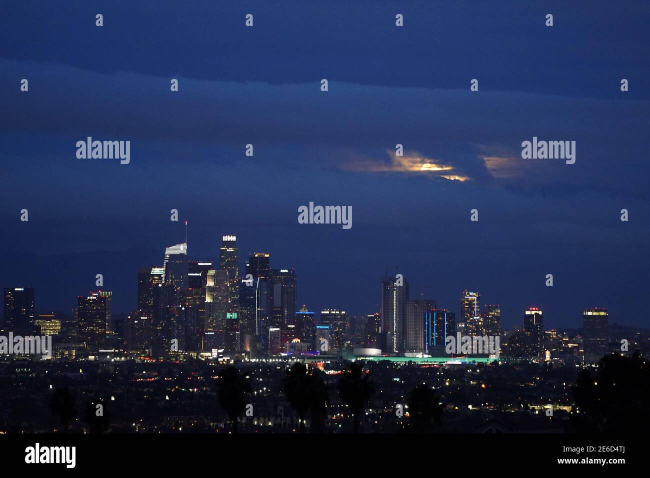 A full moon rises through storm clouds over the downtown Los Angeles ...