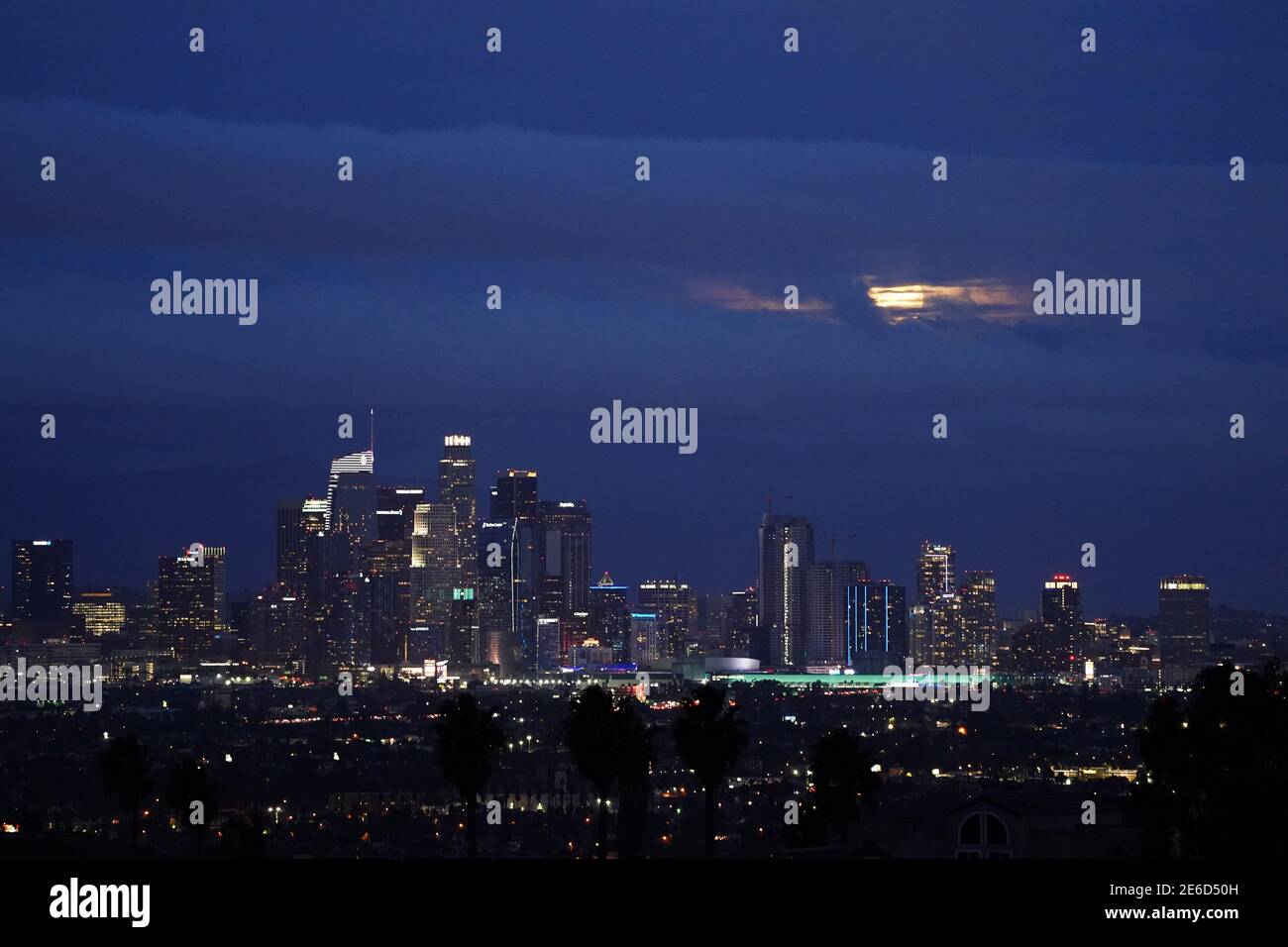 A full moon rises through storm clouds over the downtown Los Angeles ...