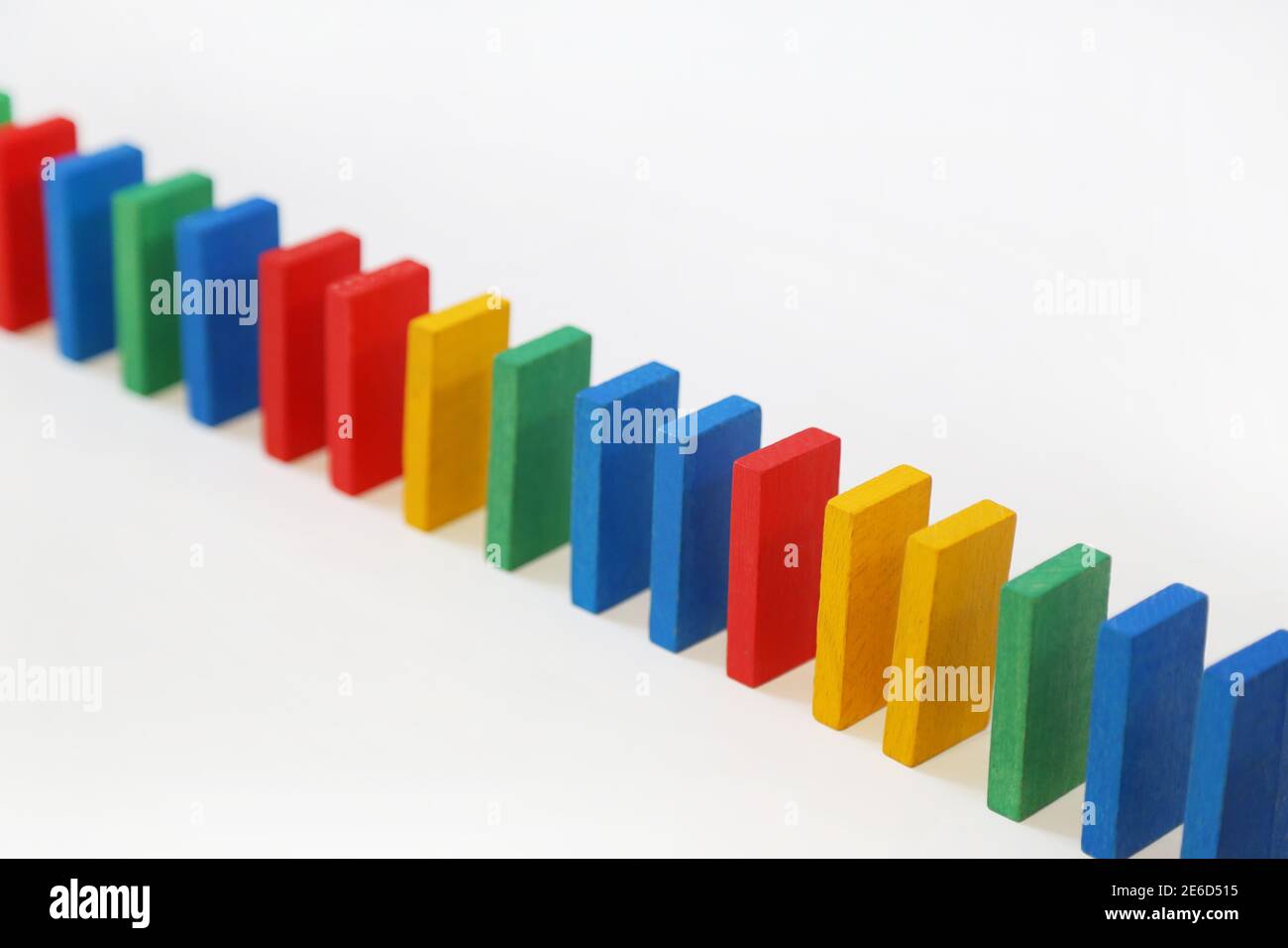 Colored dominoes stand in a row on a white background. A chain reaction ...