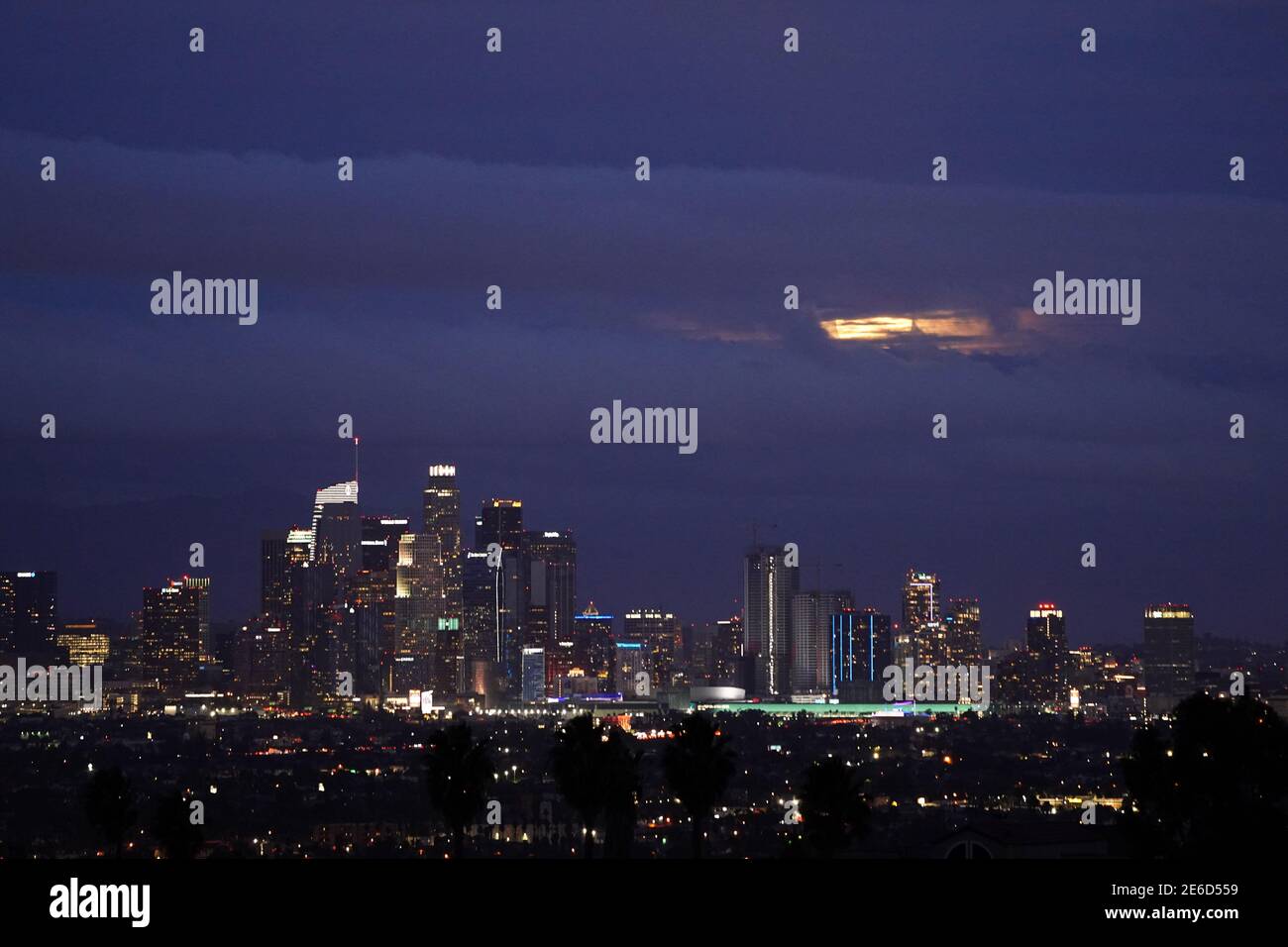 A full moon rises through storm clouds over the downtown Los Angeles ...