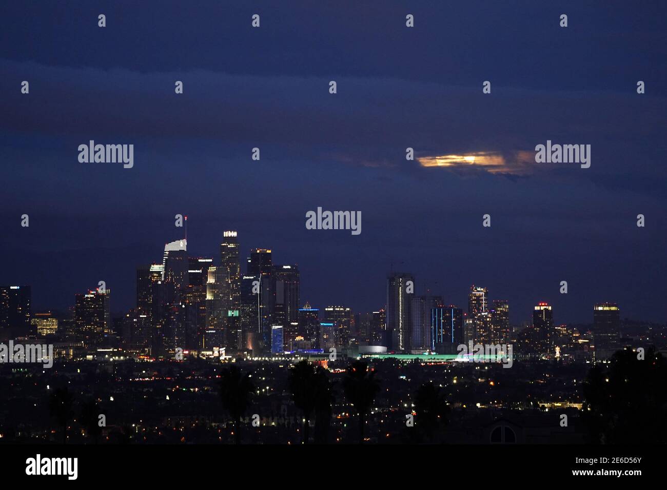 A full moon rises through storm clouds over the downtown Los Angeles ...