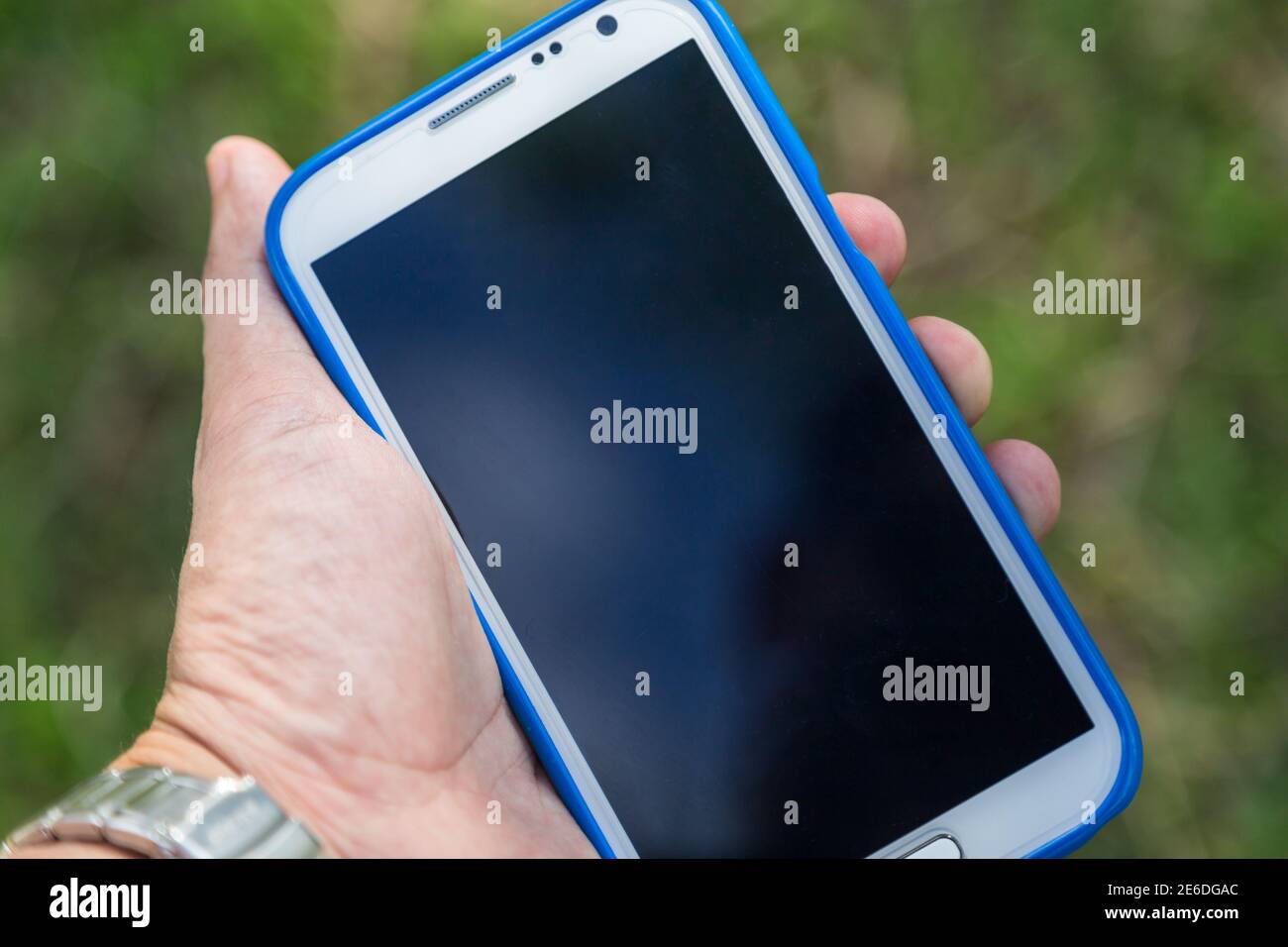 Side view of a man hand holding a modern slick smartphone against a ...