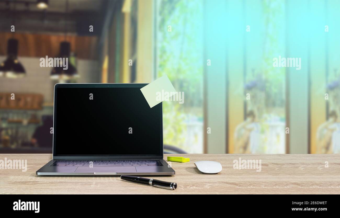 Computer laptop with empty sticky note on wooden desk in a cafe in the ...