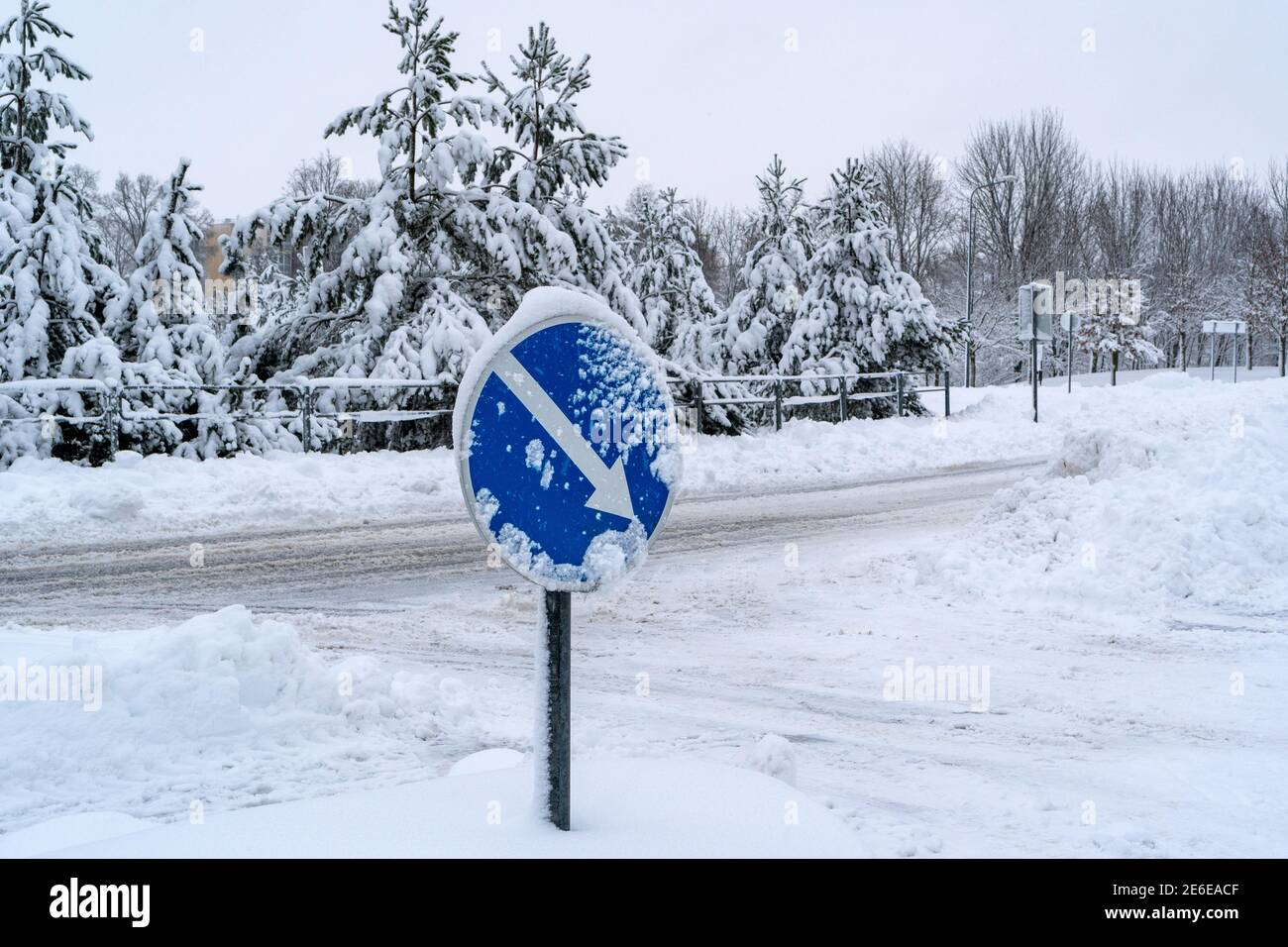 Blue traffic sign with arrow indicating driving direction. Winter ...