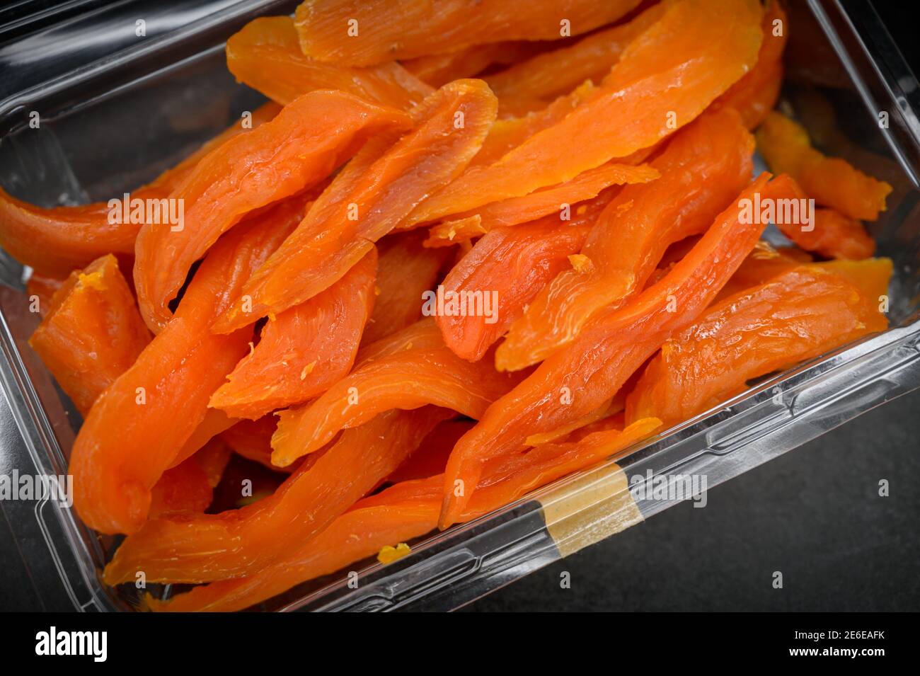 Dried mango on a in a plastic box on dark background. Selective focus ...
