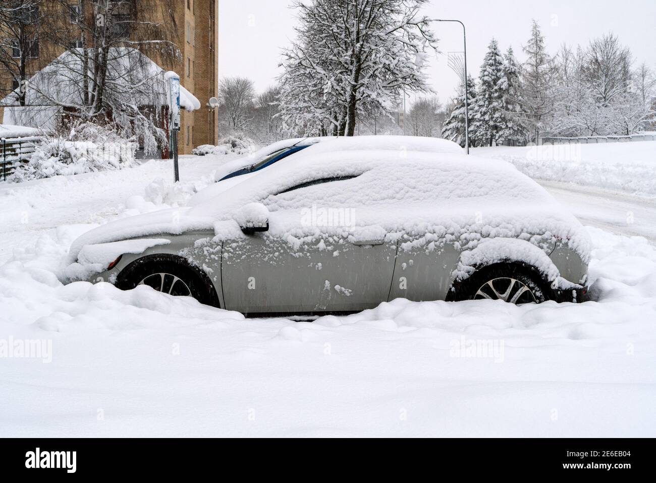 Vehicles covered with snow in the winter blizzard in the parking lot ...