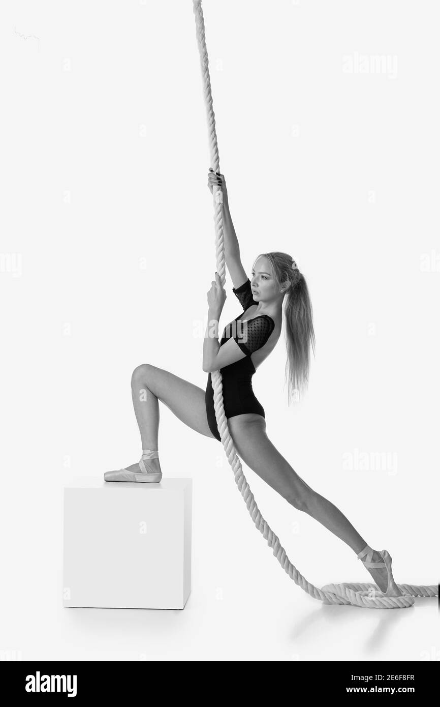 beautiful ballerina in pointe shoes is posing with rope on white studio ...
