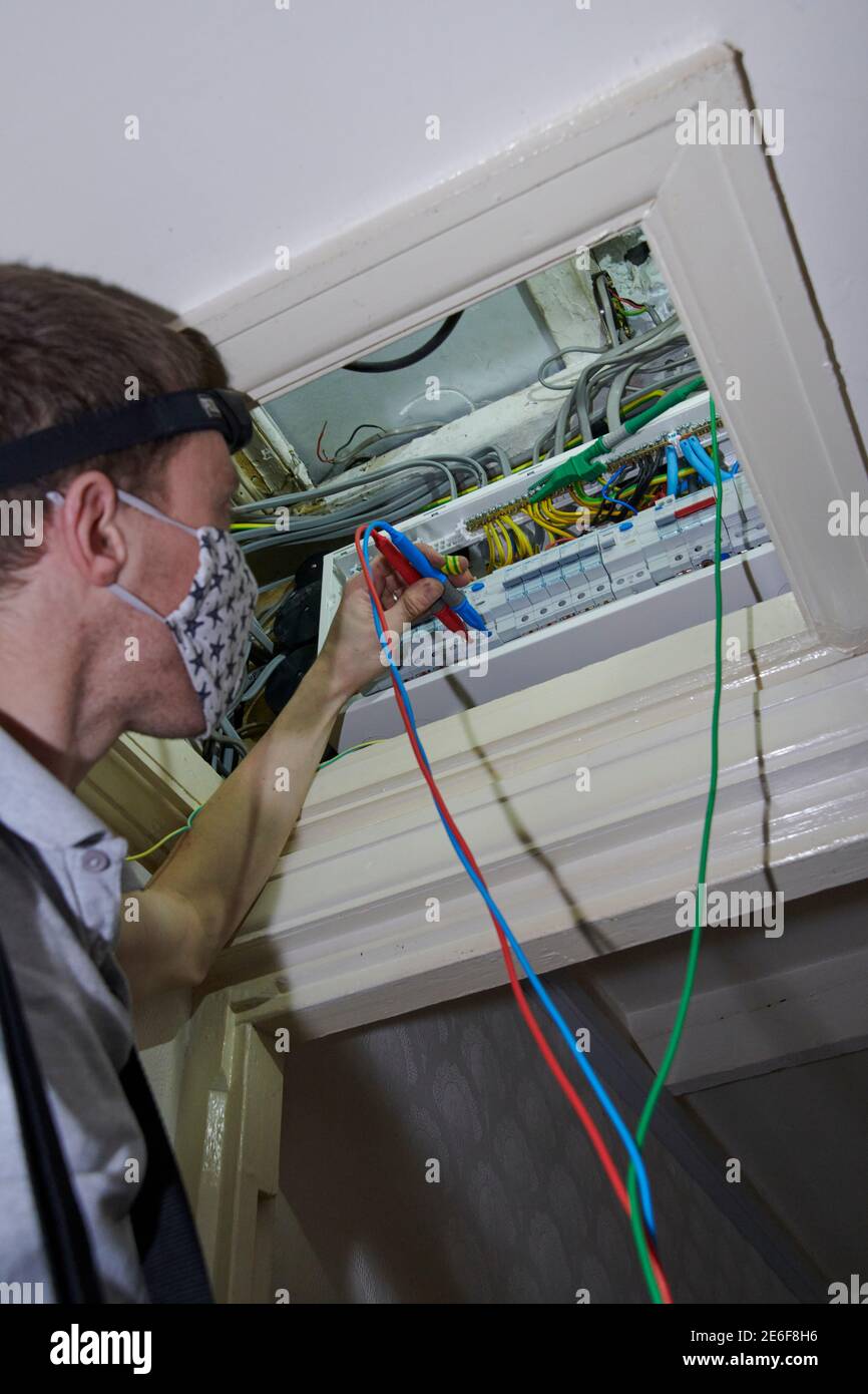 Electrician refitting and testing a new fuse board and safety checking ...