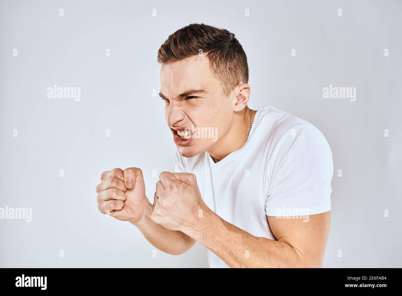 Emotional man gestures with his hands displeasure white t-shirt light ...