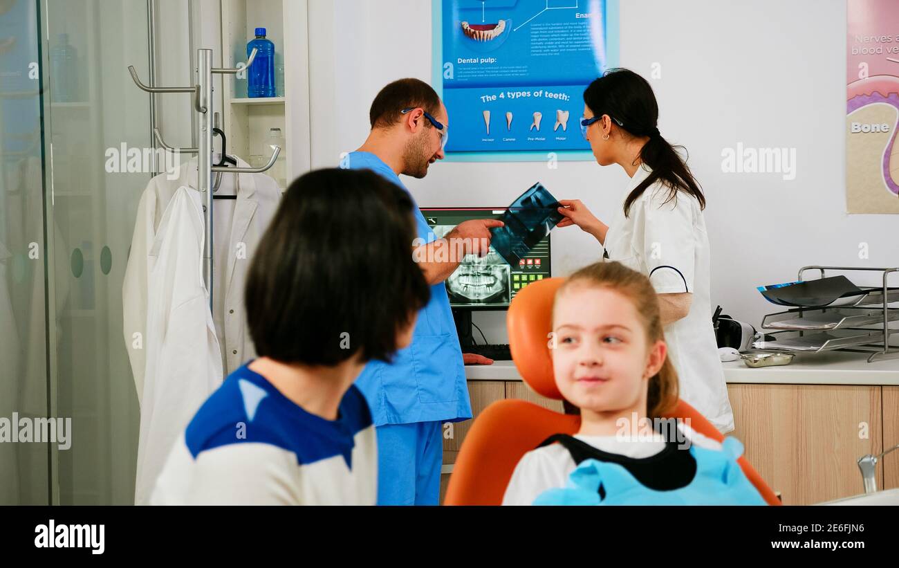 Team of stomatologist doctors analysing teeth x-ray of little patient ...