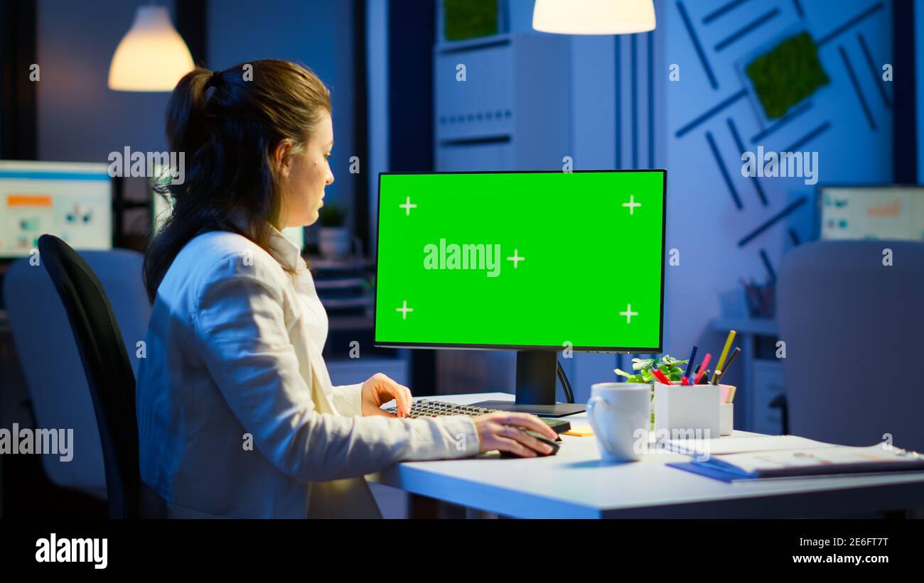 Woman looking at computer with chroma key during night time in start up ...