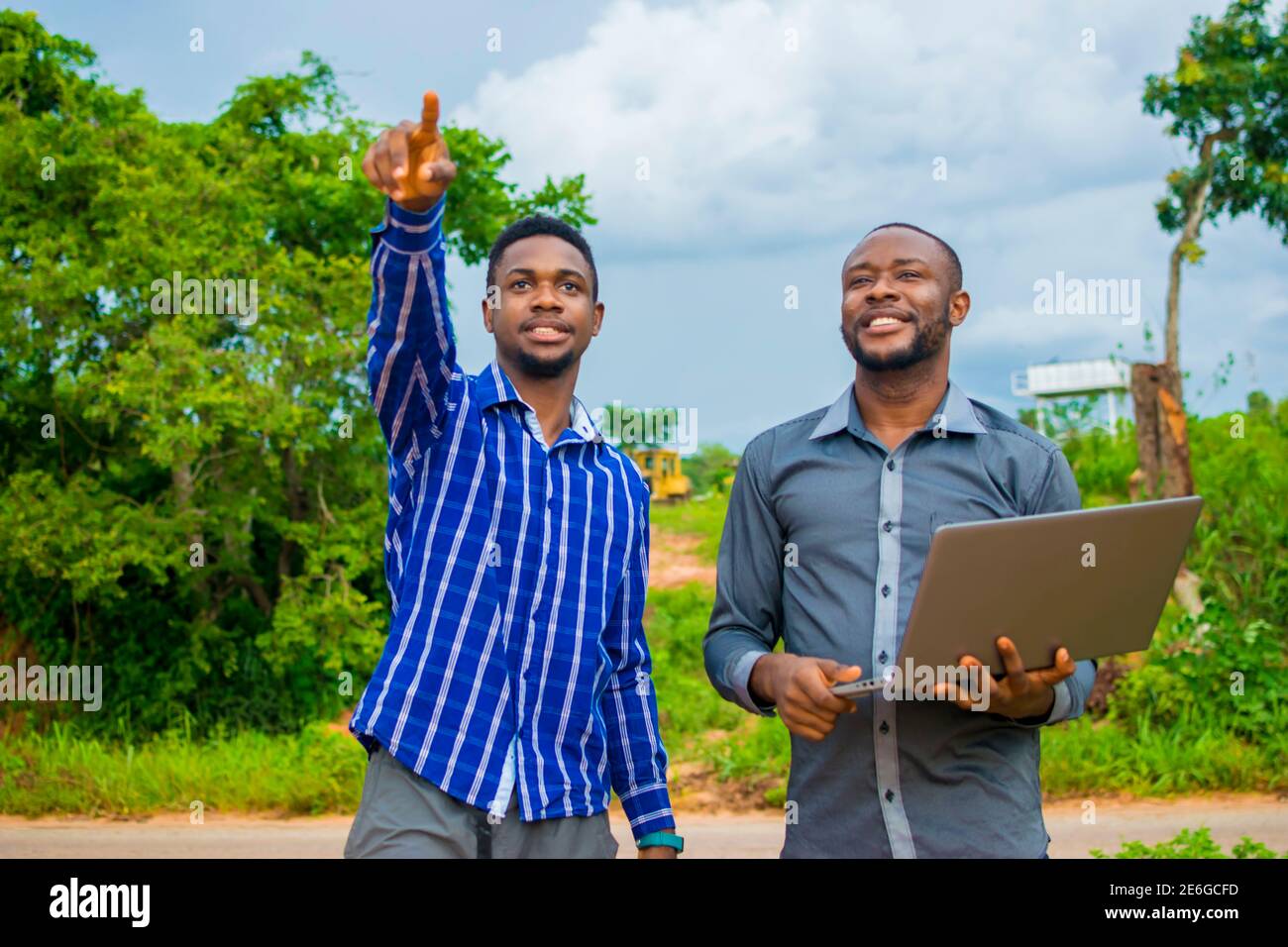 young black man pointing at some places on a farmland for another man ...
