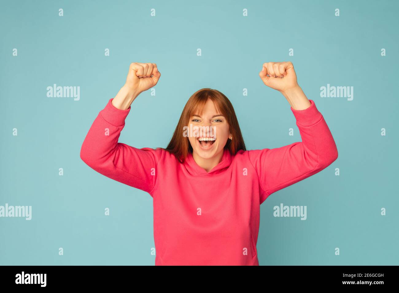 Winner overjoy. Caucasian woman's portrait isolated on blue studio ...