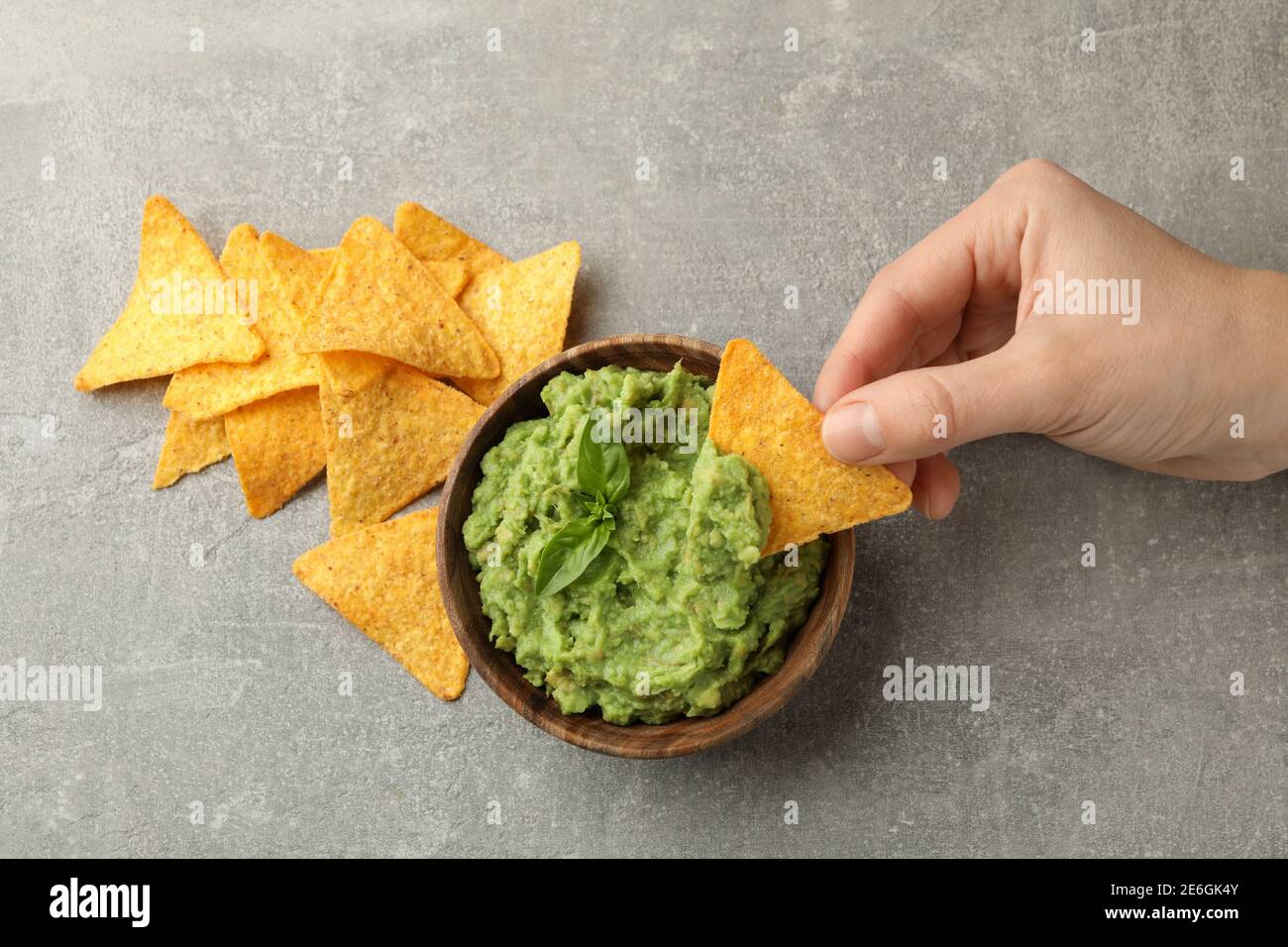 Female hand dips chips slice in guacamole, top view Stock Photo - Alamy