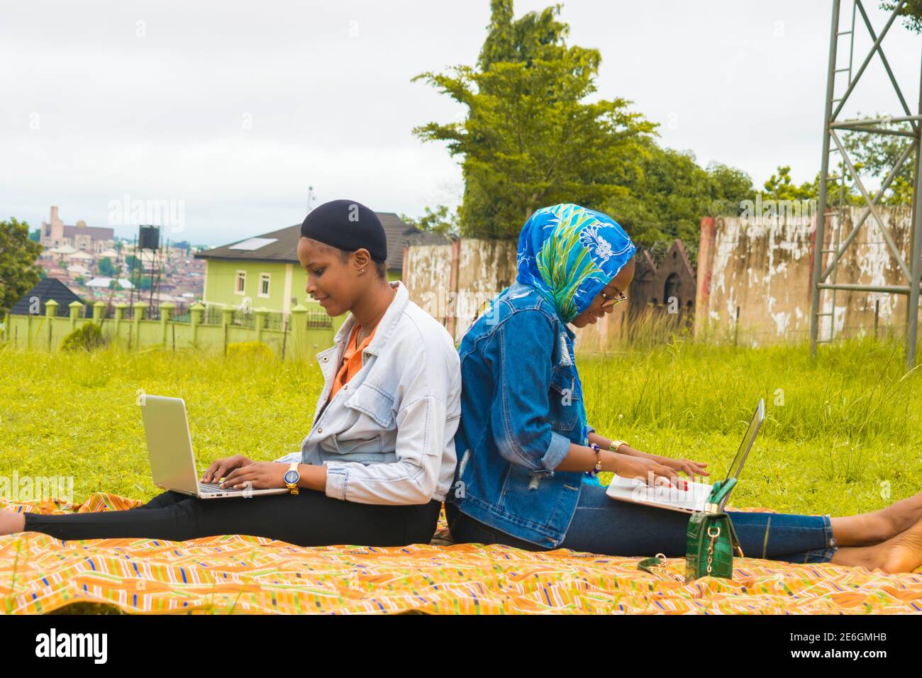 young beautiful black ladies sitting outside, using their laptops and ...