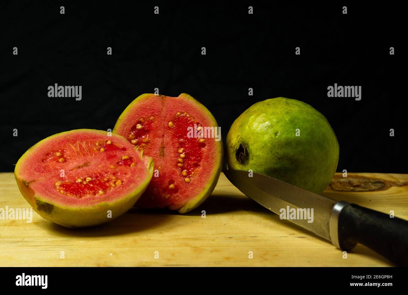 Guava fruit cut into pieces and kept on the table alongside a full ...