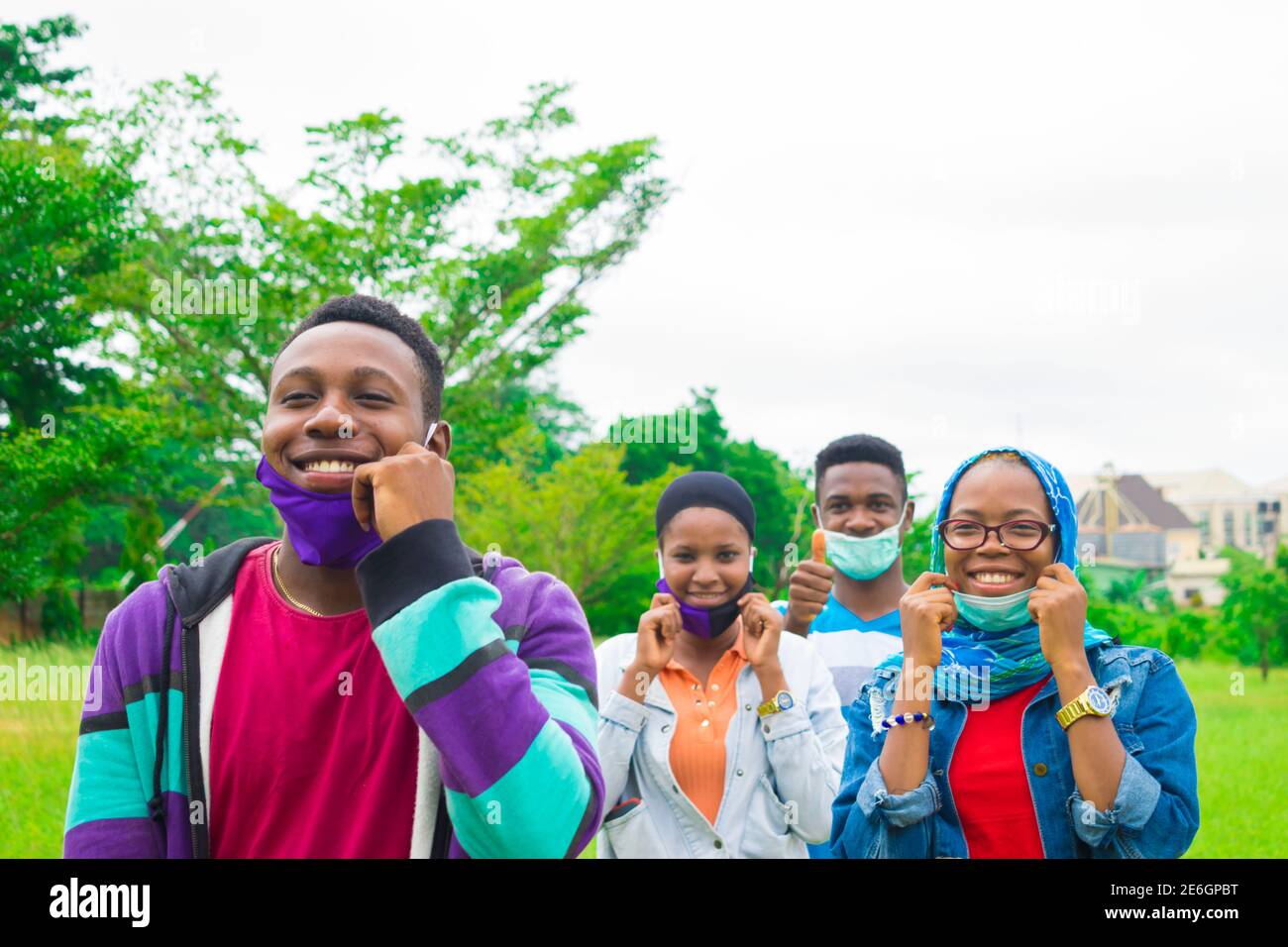 young black friends standing while trying to wear their nose masks in a ...