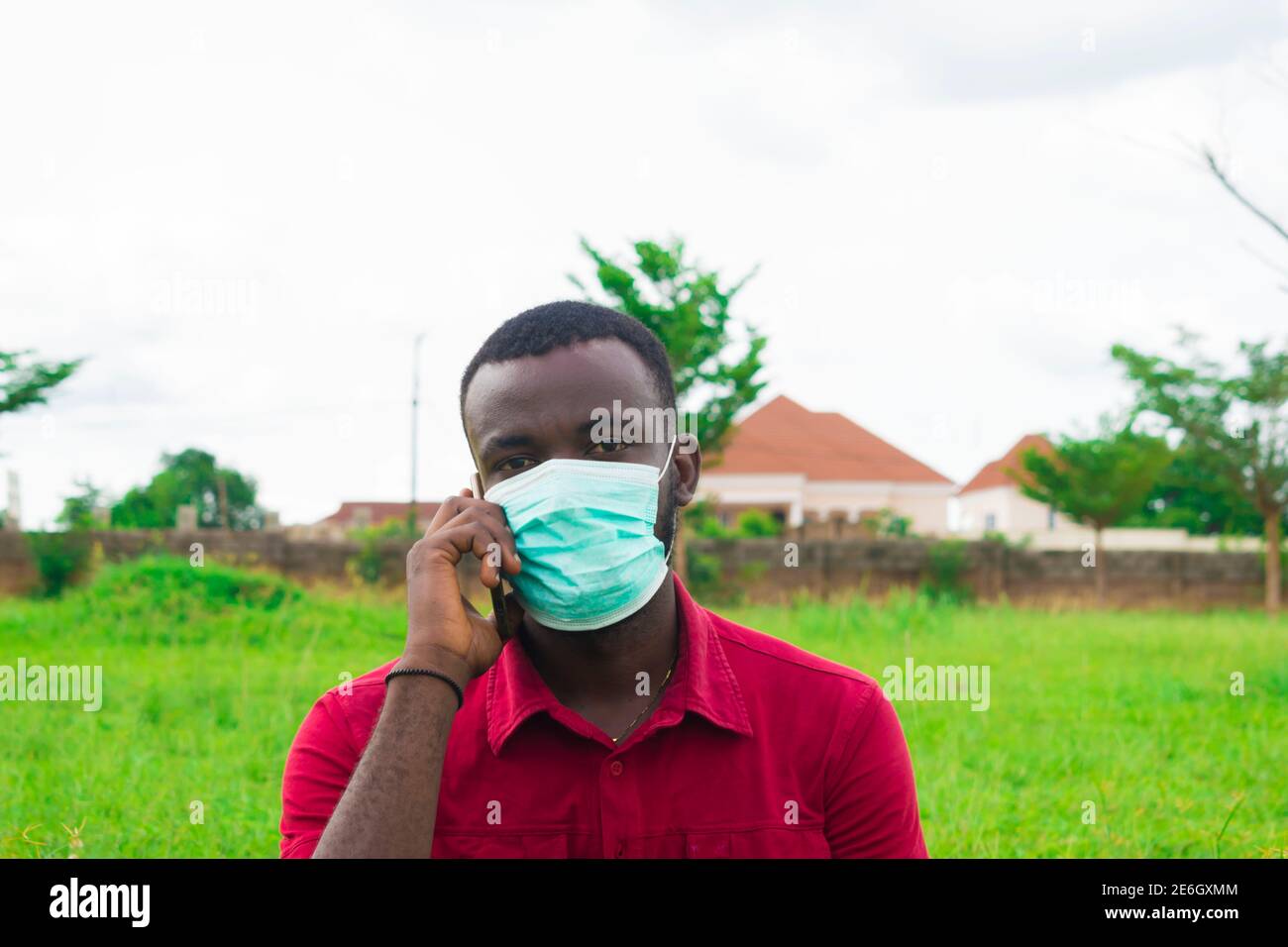 young black man wearing a nose mask, sitting down and using his ...