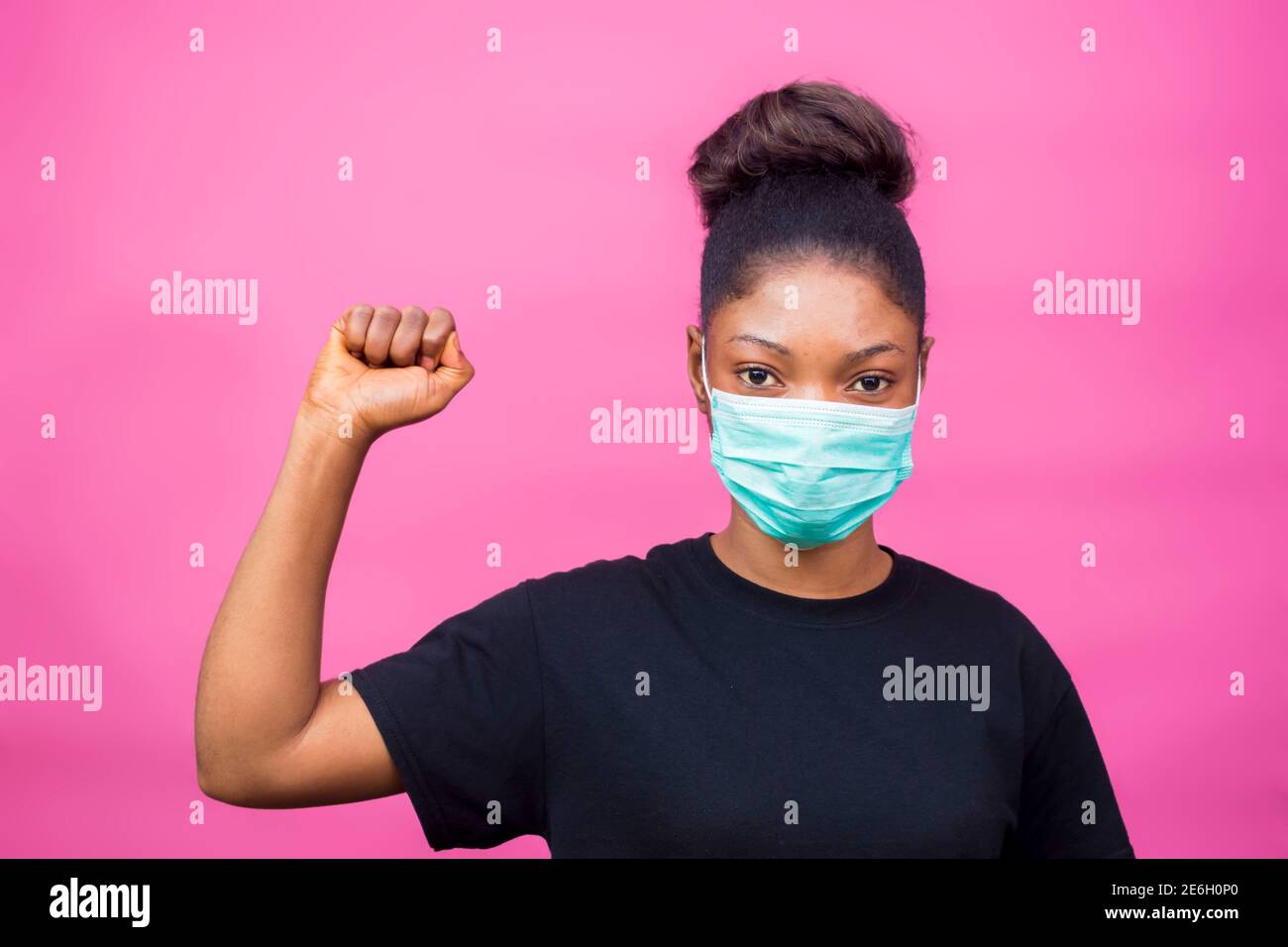 young beautiful black lady wearing a nose mask with a fist of ...