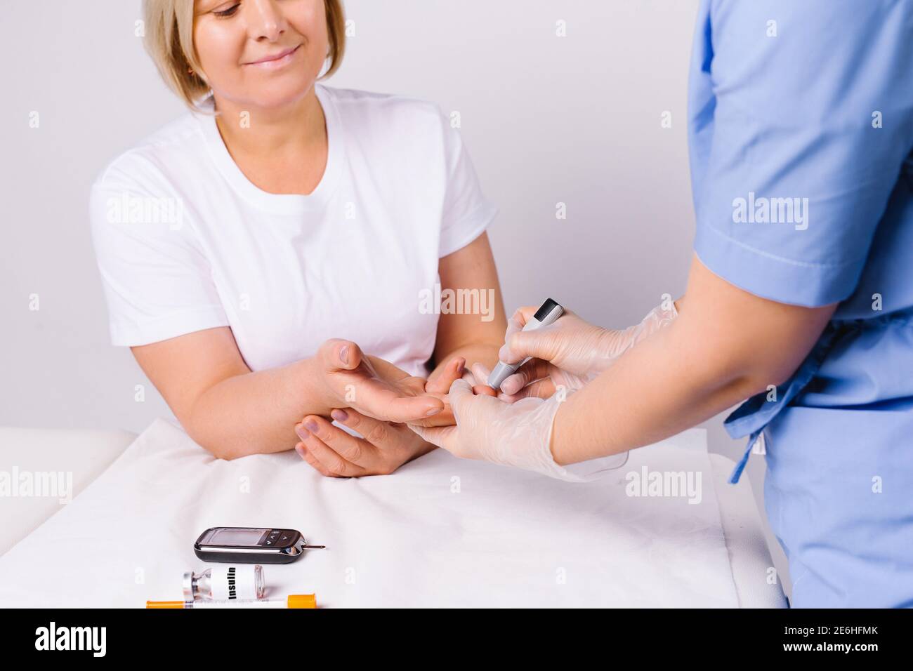 Hands of a healthcare professional using a glucometer to take an ...