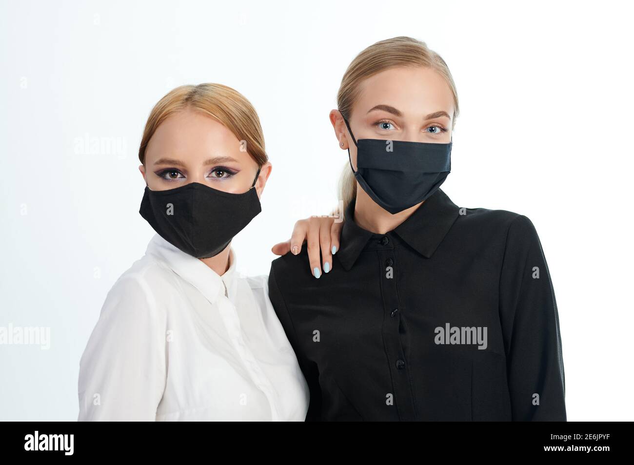 Happy two young girls in black mask isolated on white studio background ...