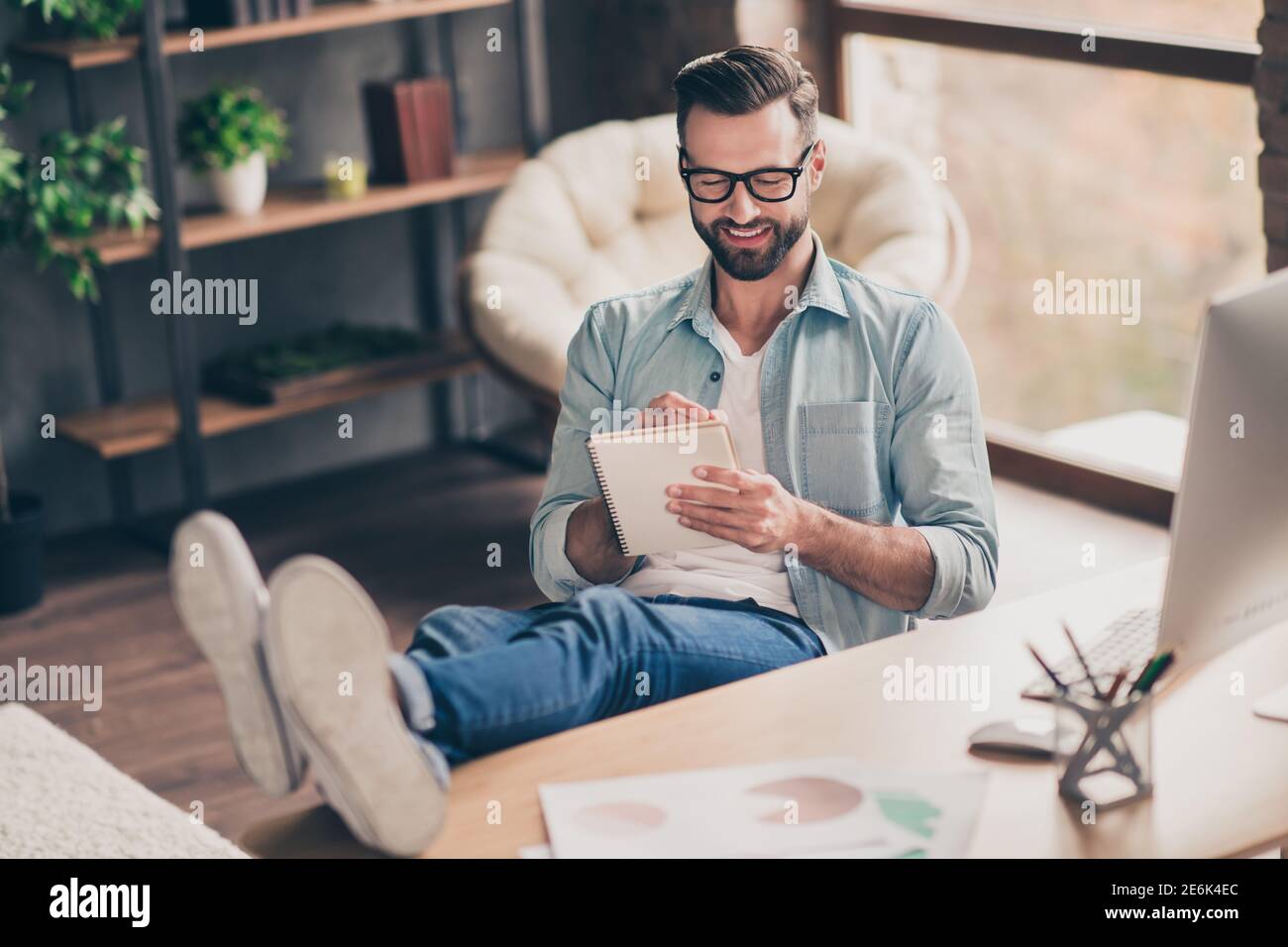 Photo portrait of man taking notes with legs on table in modern ...